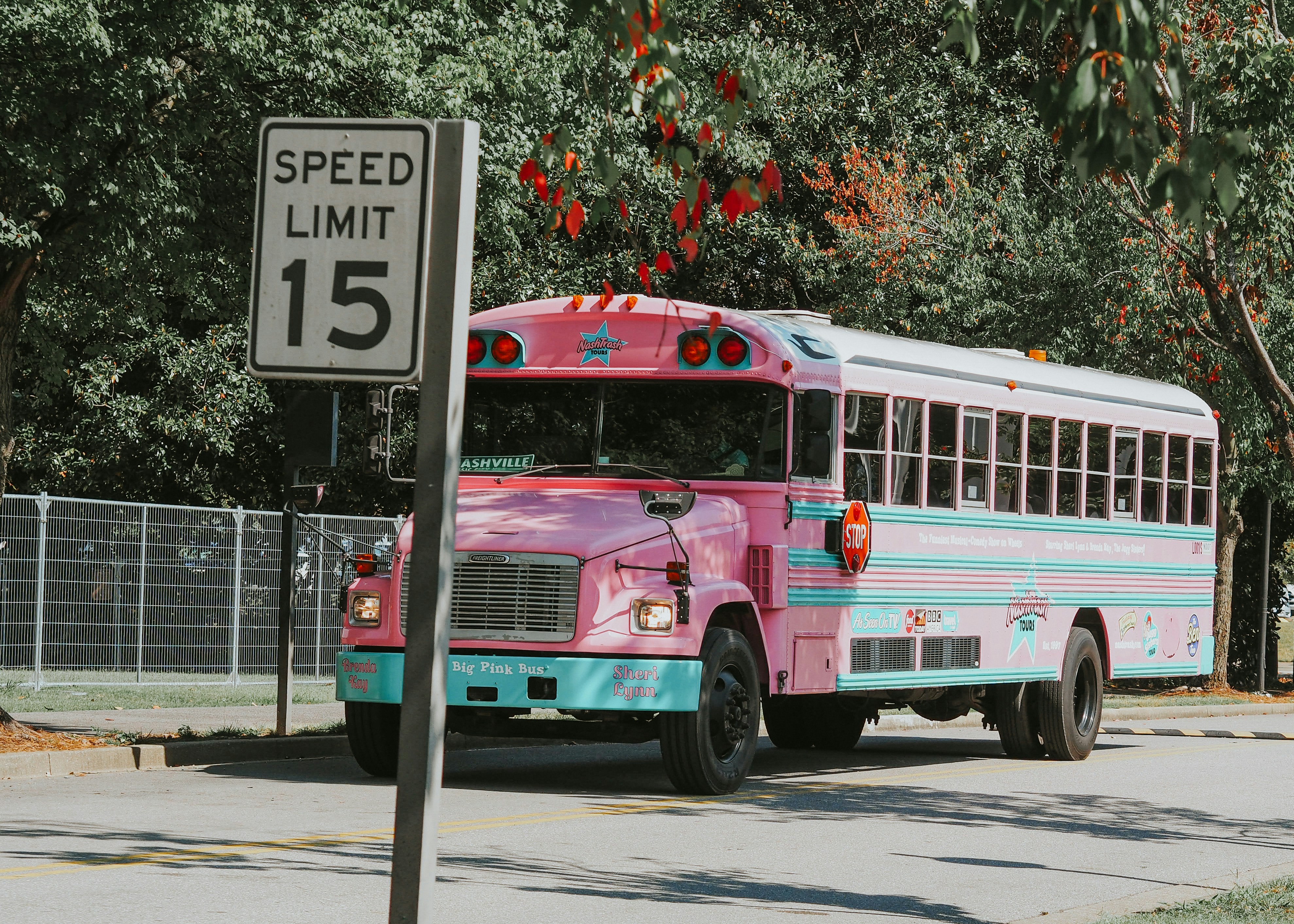 A pink and blue school bus parked next to a speed limit sign photo ...