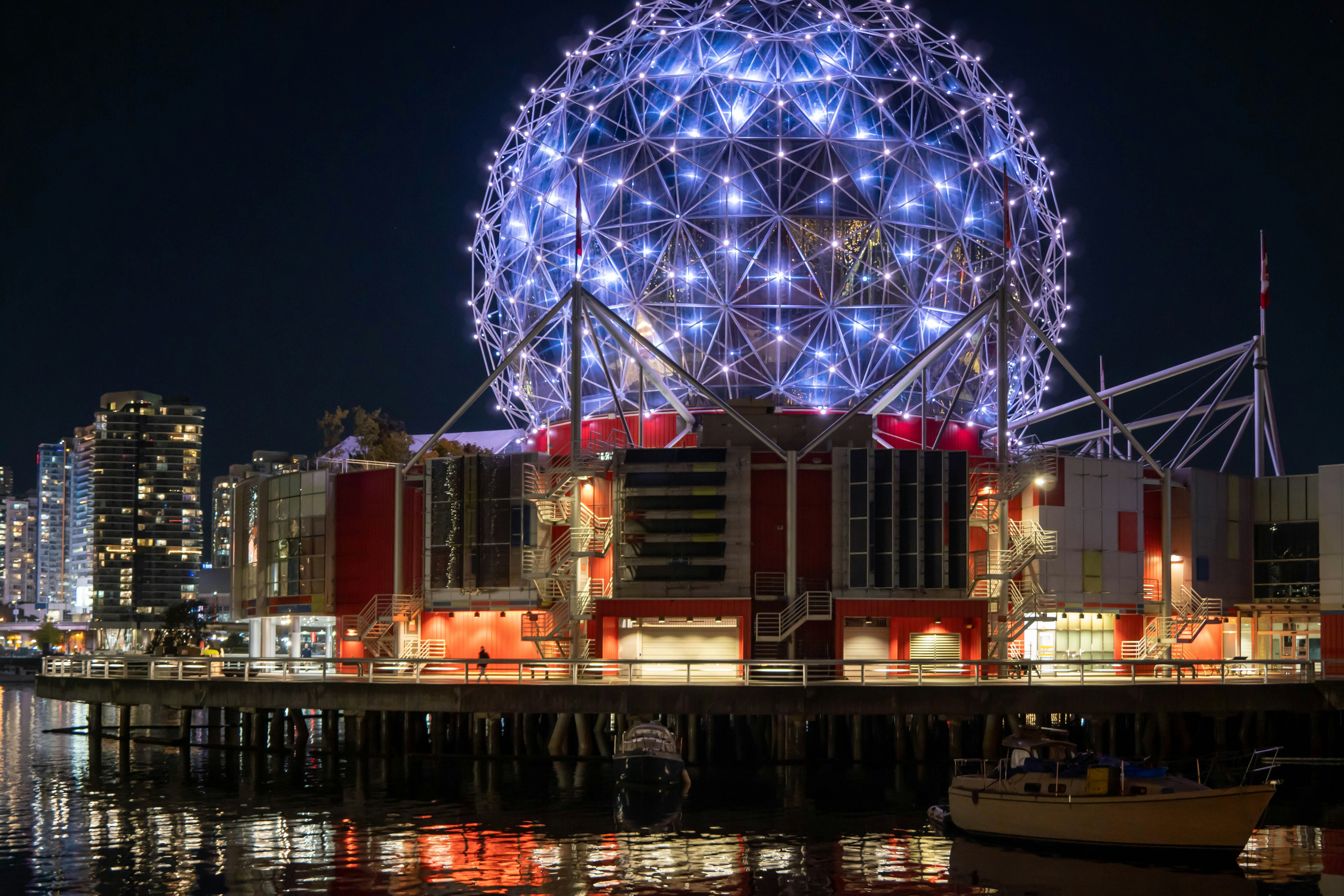 Blue Geodesphere Over a Red-Panel Waterfront at Night