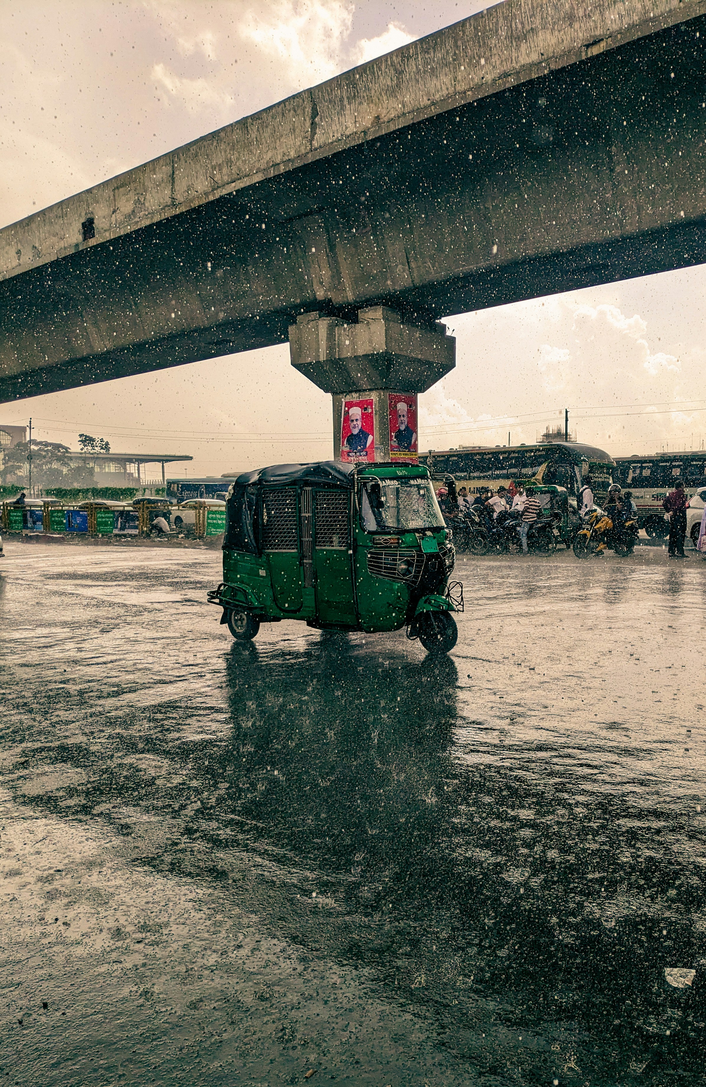A green vehicle driving under a bridge in the rain photo – Free Road ...