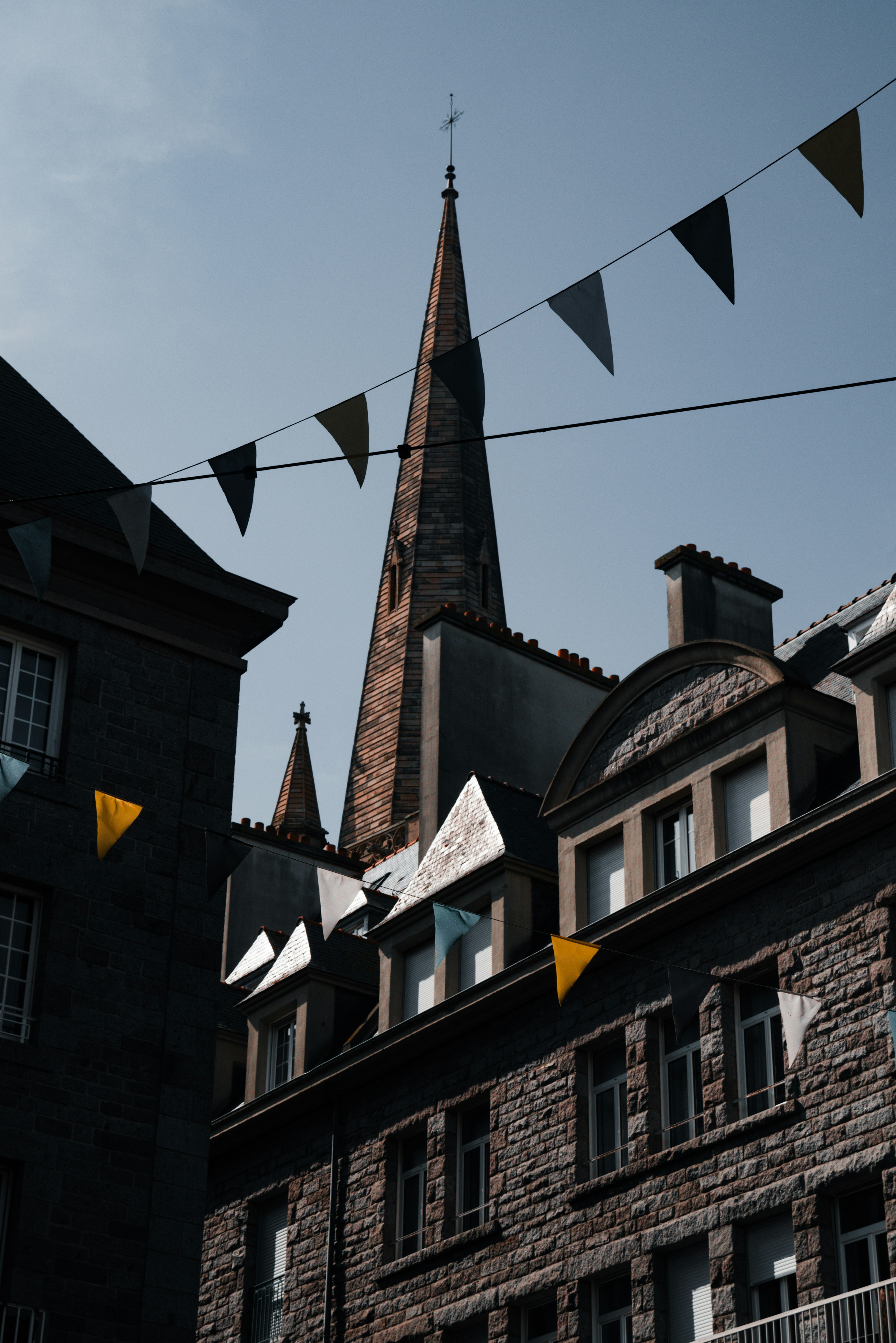 Spire and bunting over a brick-town roofscape