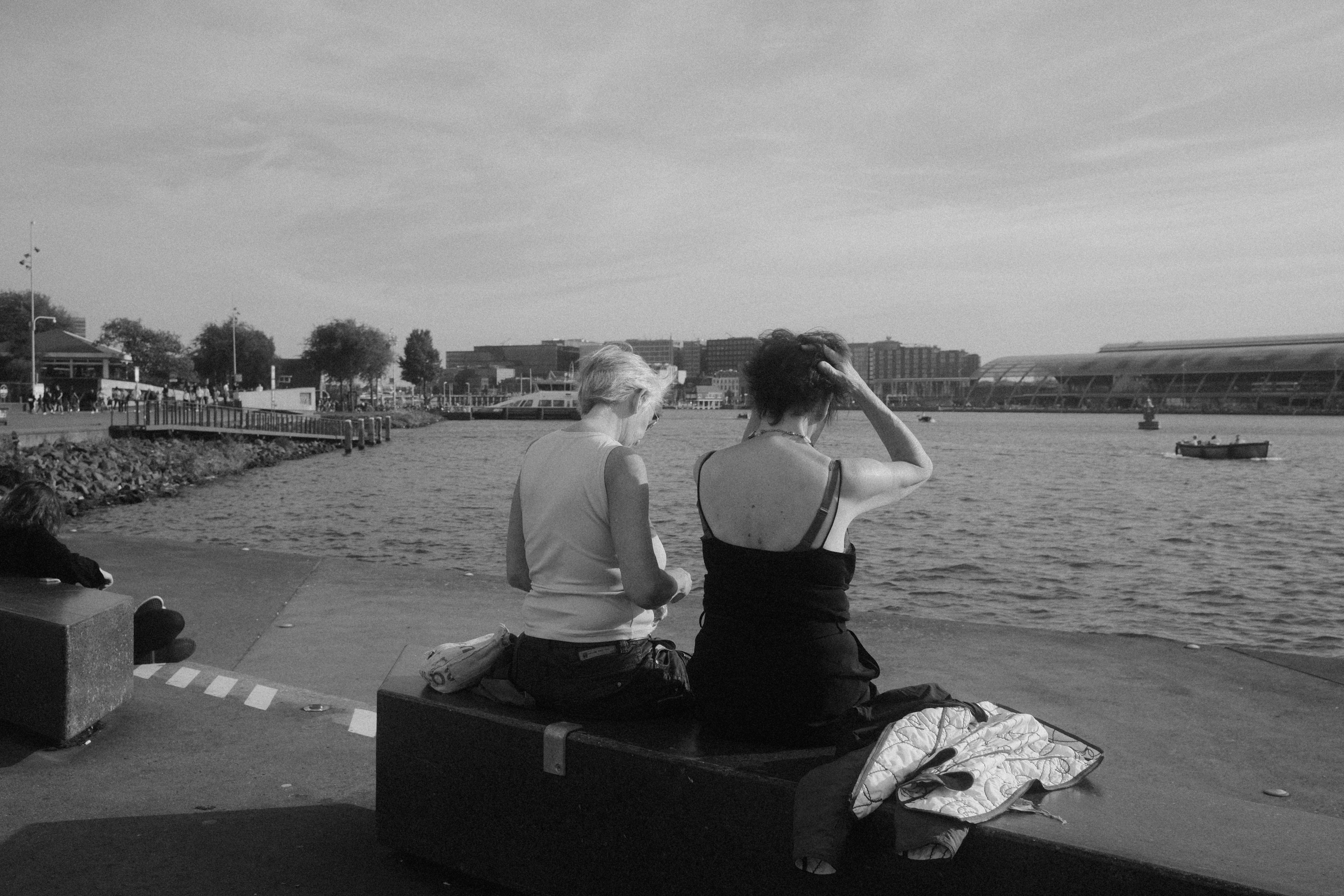 Quiet Confidences by the Harbor: Two Women on a Seaside Bench