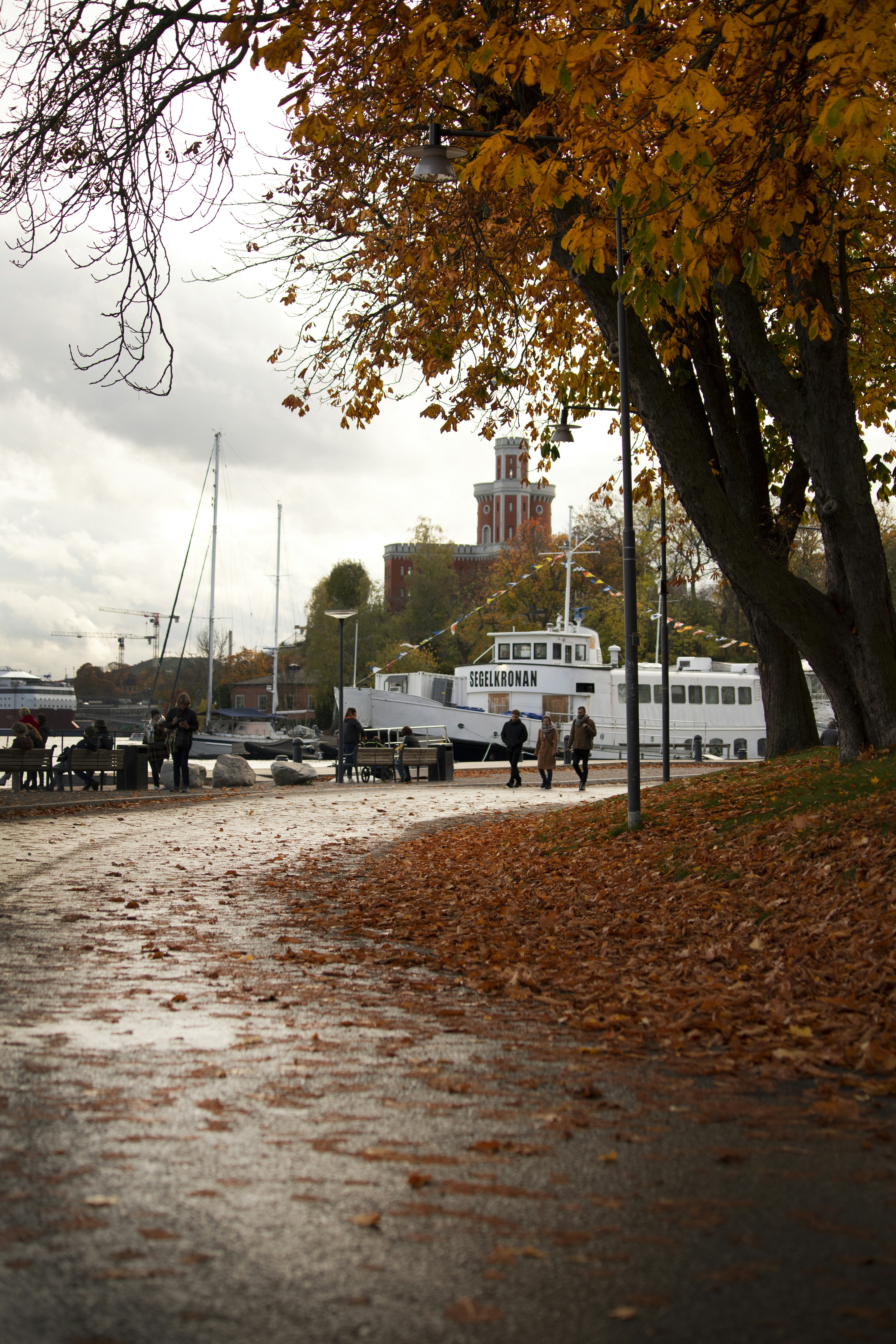 Autumn riverside promenade with a distant boat and church tower