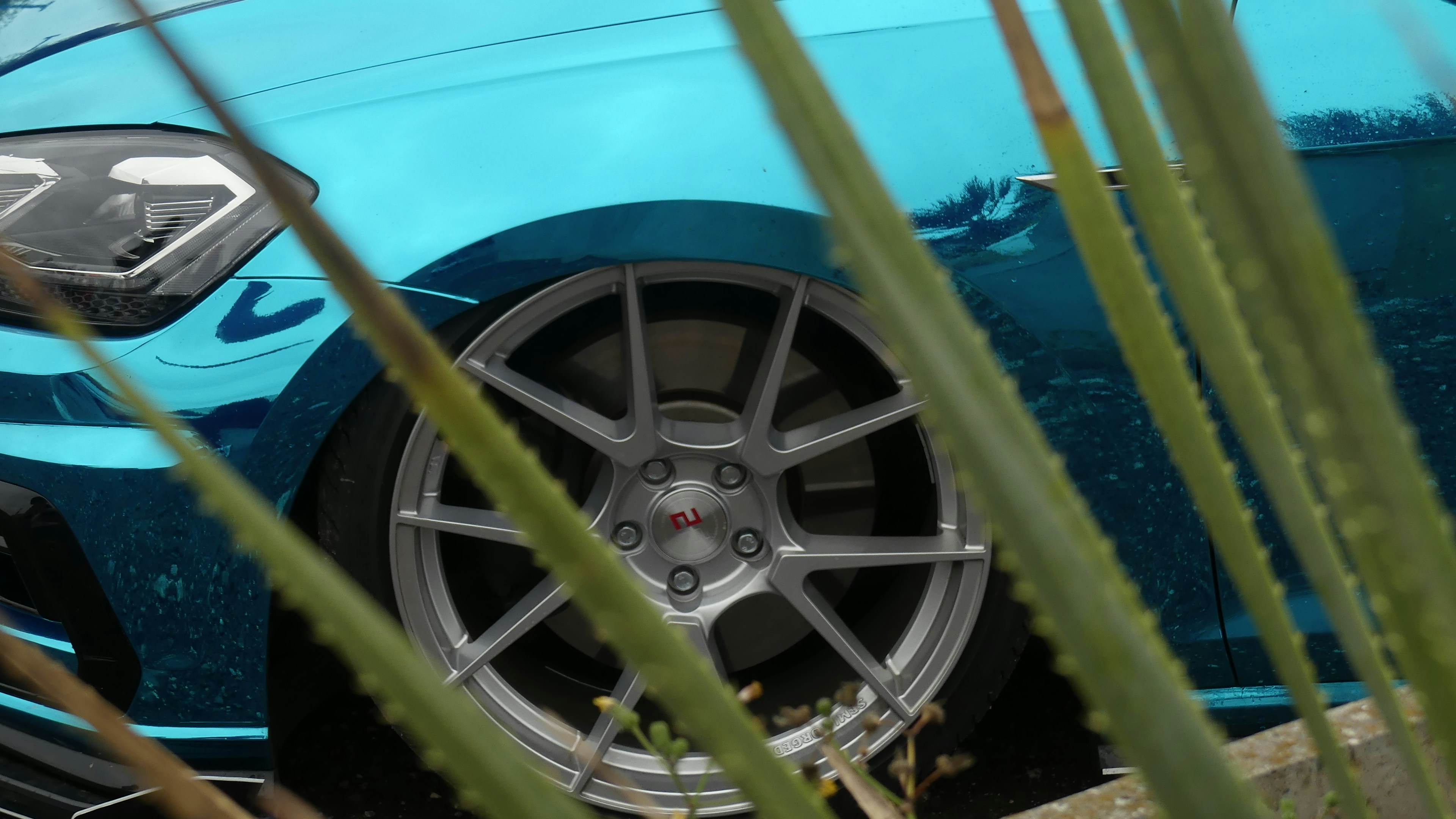 a close up of a blue car parked on the side of the road