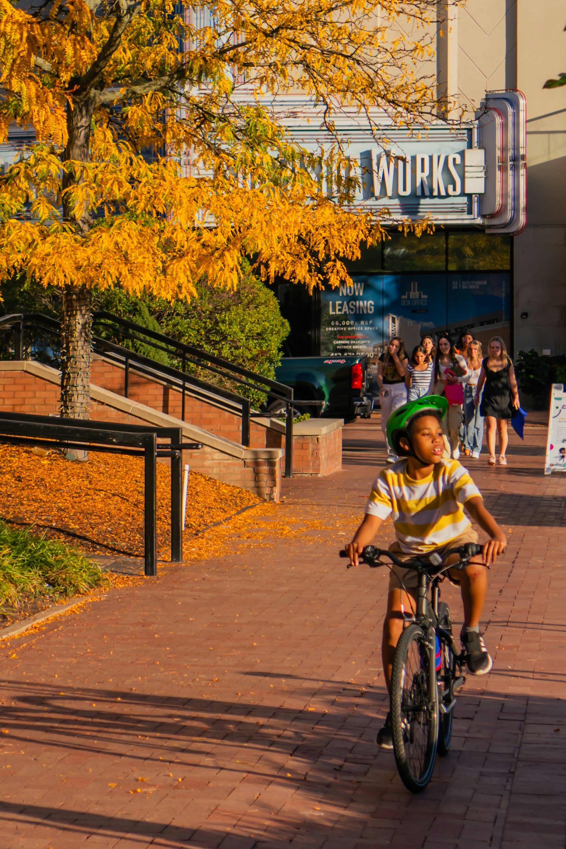 Ride Through Autumn: A Child on a Bright Bicycle in a Sunny Plaza