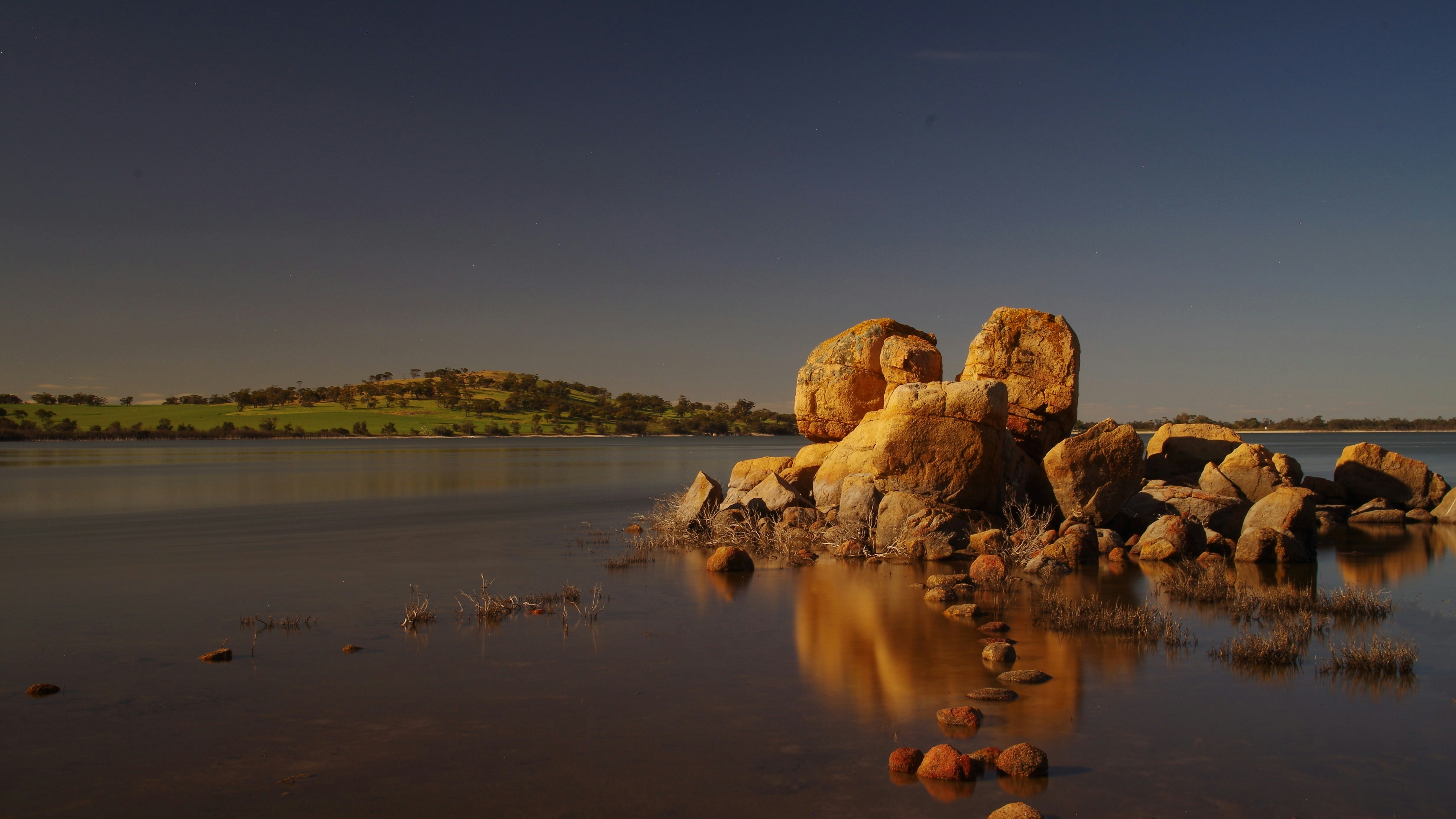 Some rocks in the water and a hill in the background photo – Free Lime ...