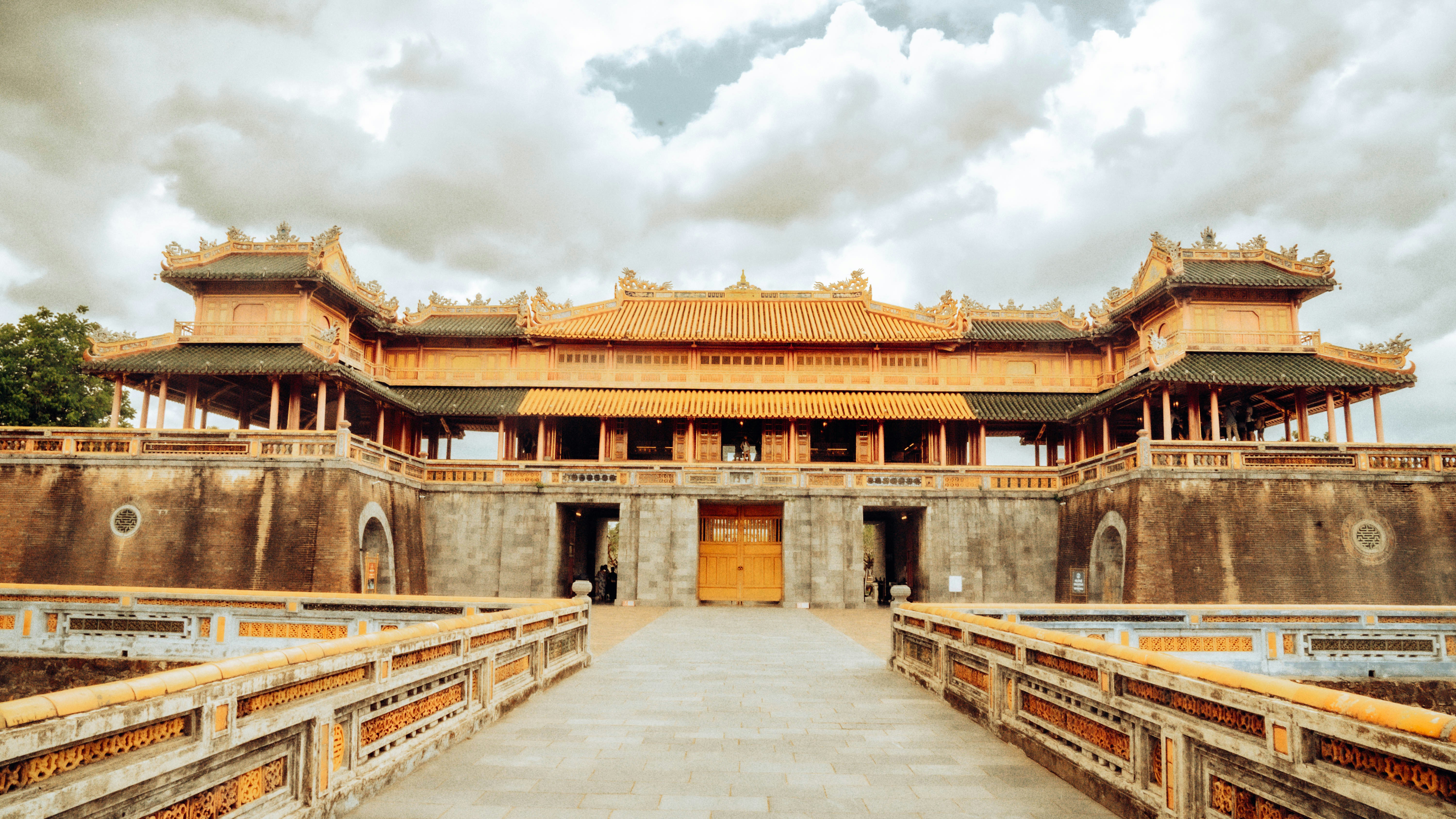 Historic palace with ornate golden roofs under a dramatic cloudy sky.
