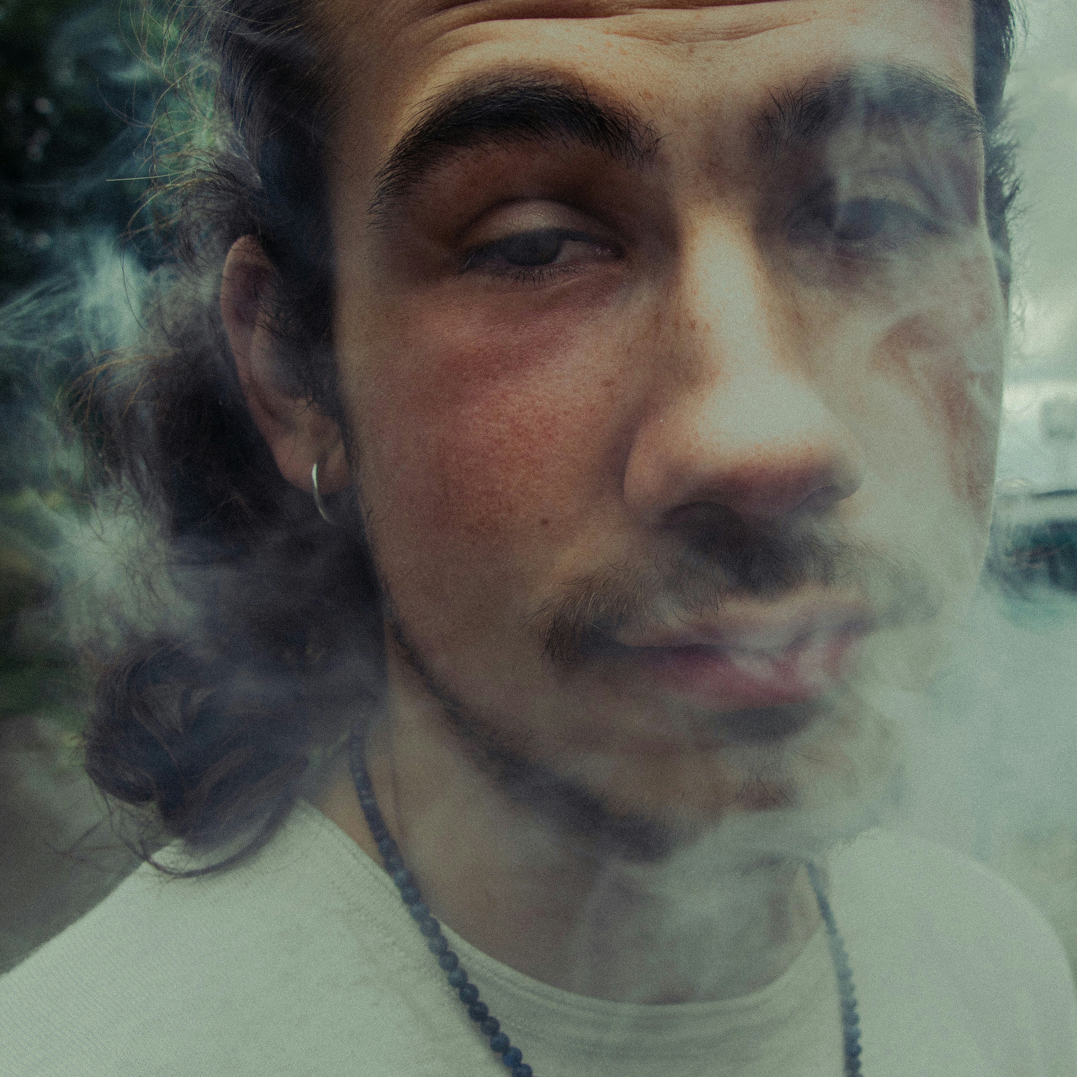 A man smoking a cigarette in front of a window photo – Free Smoke Image ...