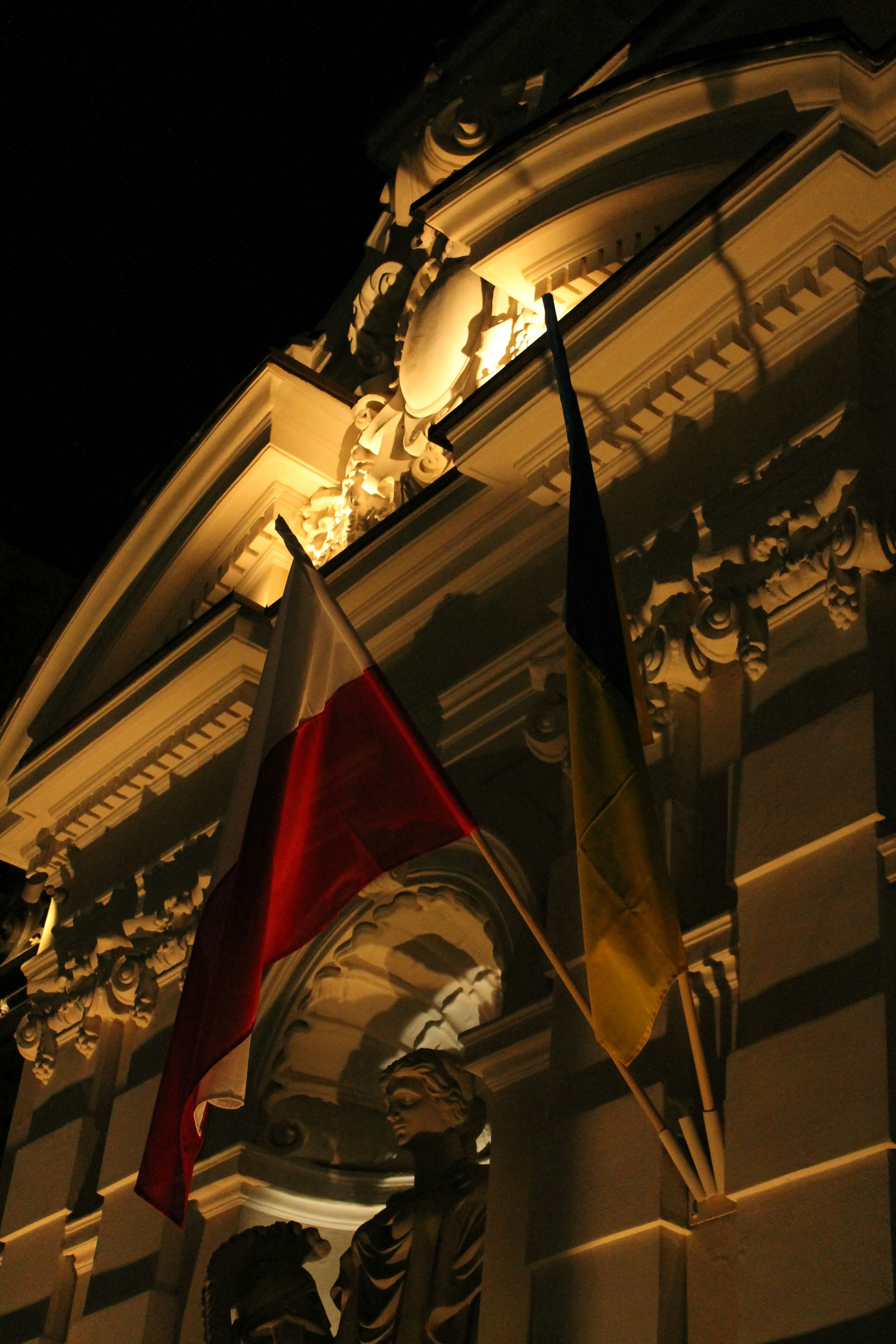Night Facade in Amber Light: Flags, Carvings, and Quiet Grandeur