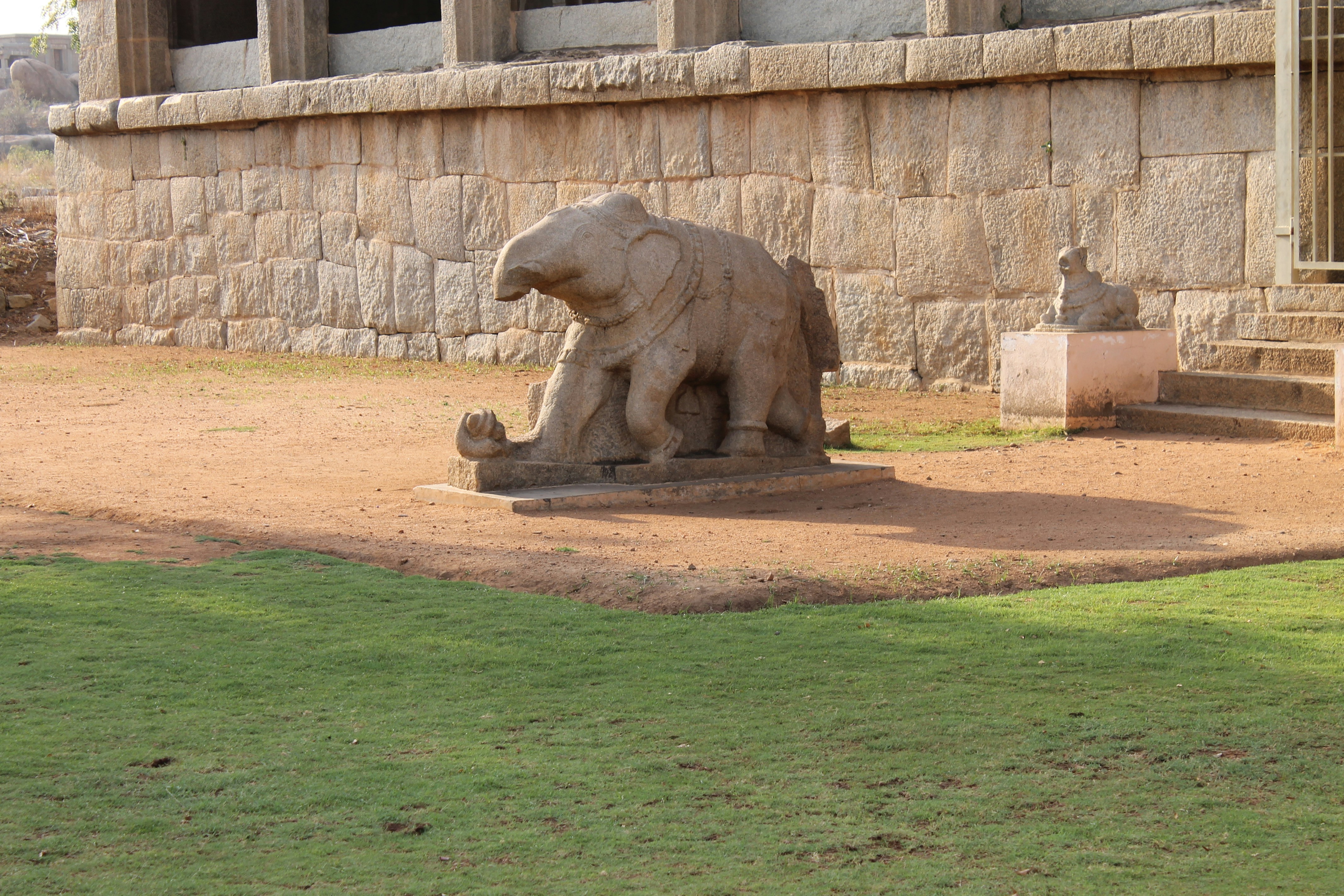 Stone Sentinel: A Dinosaur Statue Framed by a Weathered Facade