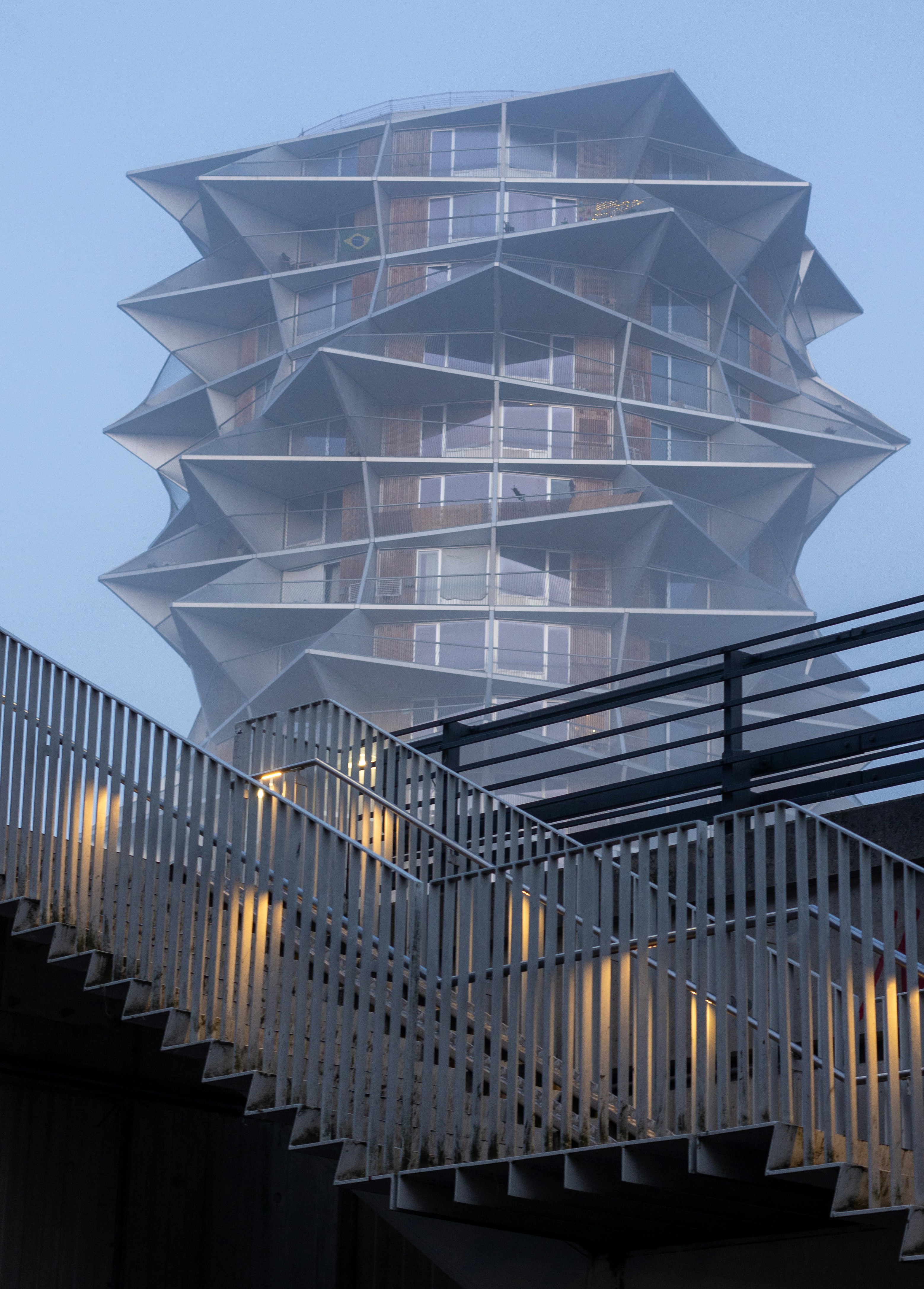 Helical Facade: A Metal Spiral Tower Rises Through Mist