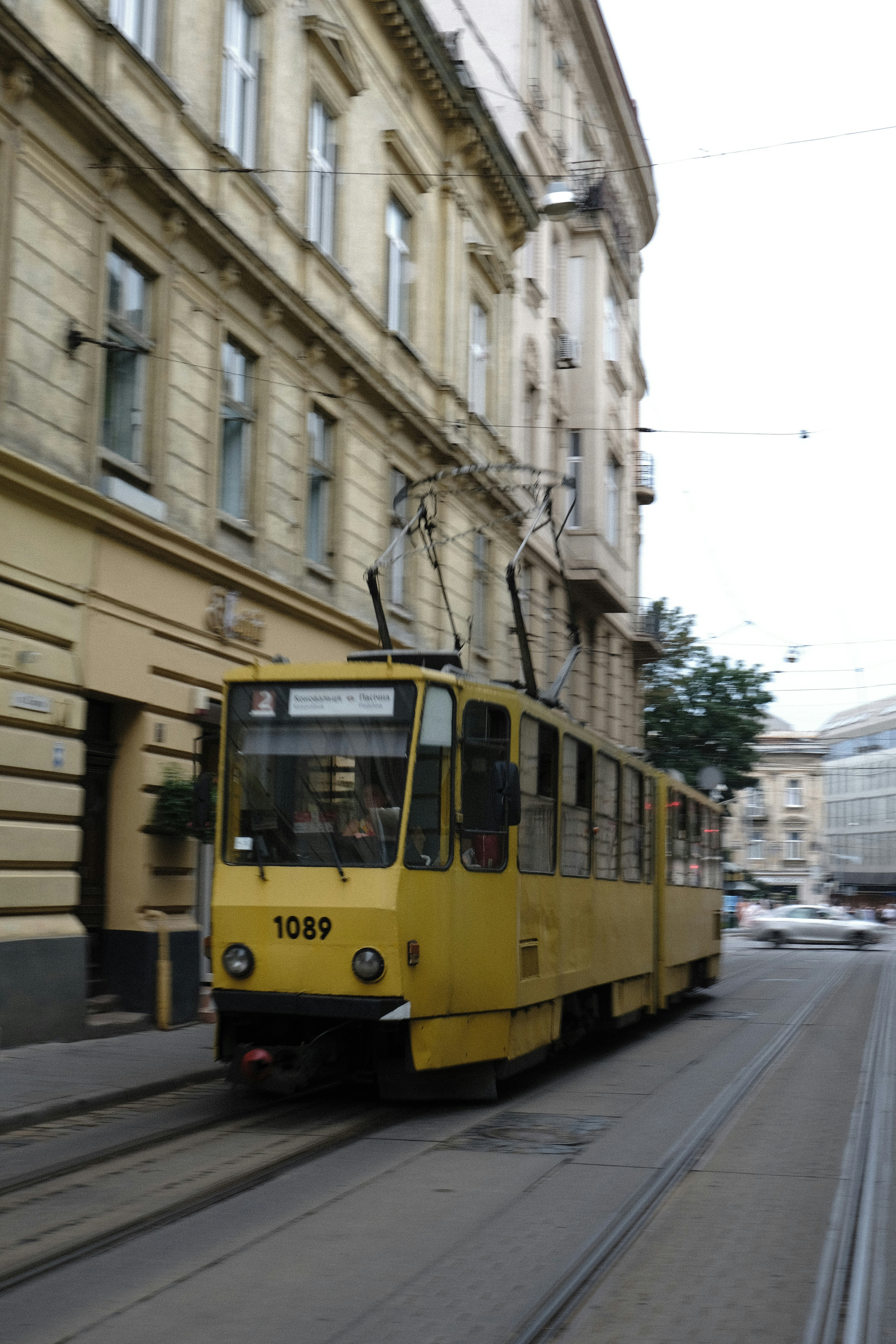 Sunlit Yellow Streetcar Bends Through a Historic Downtown Corridor