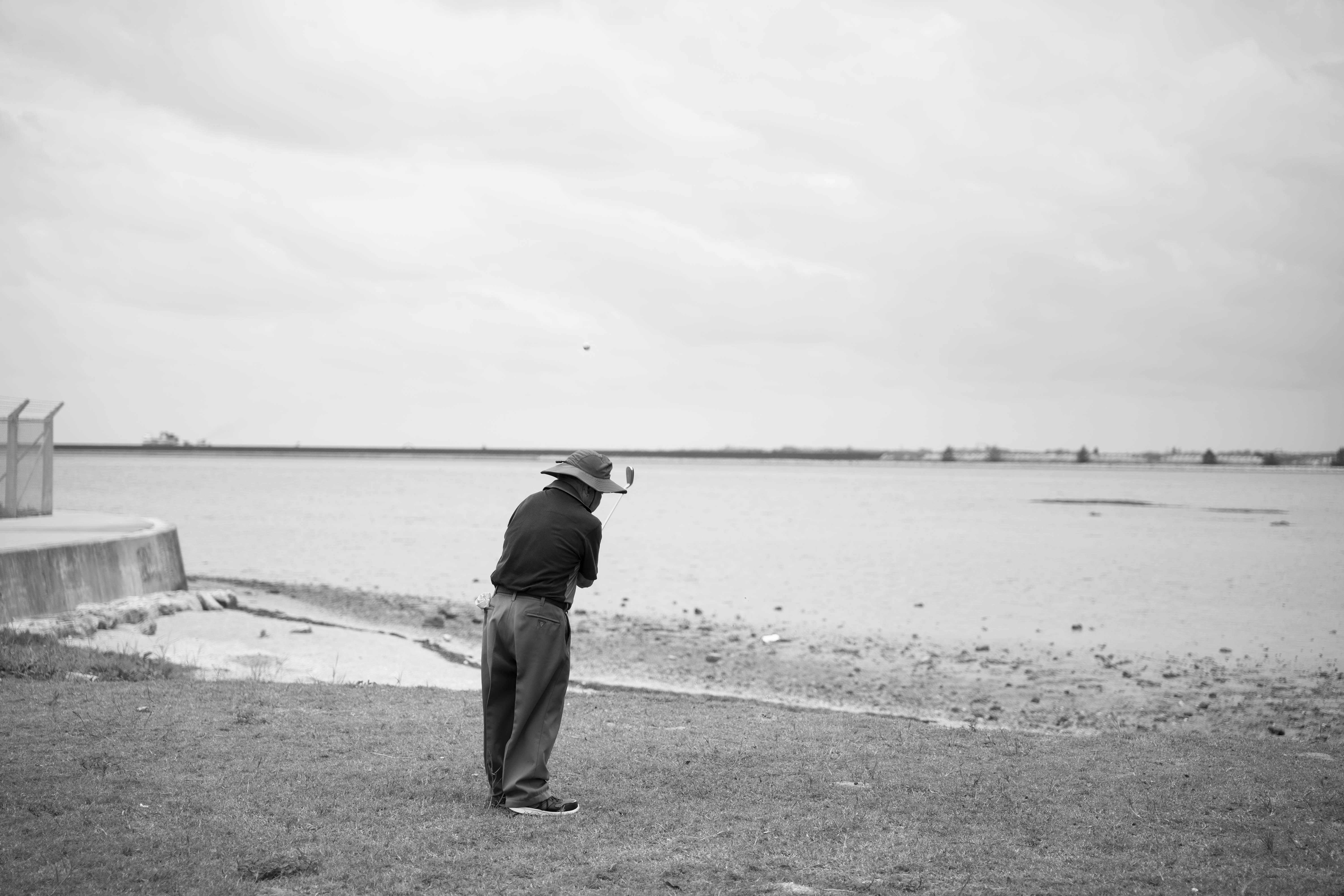 Horizon Gaze: A solitary figure in a hat at the shore