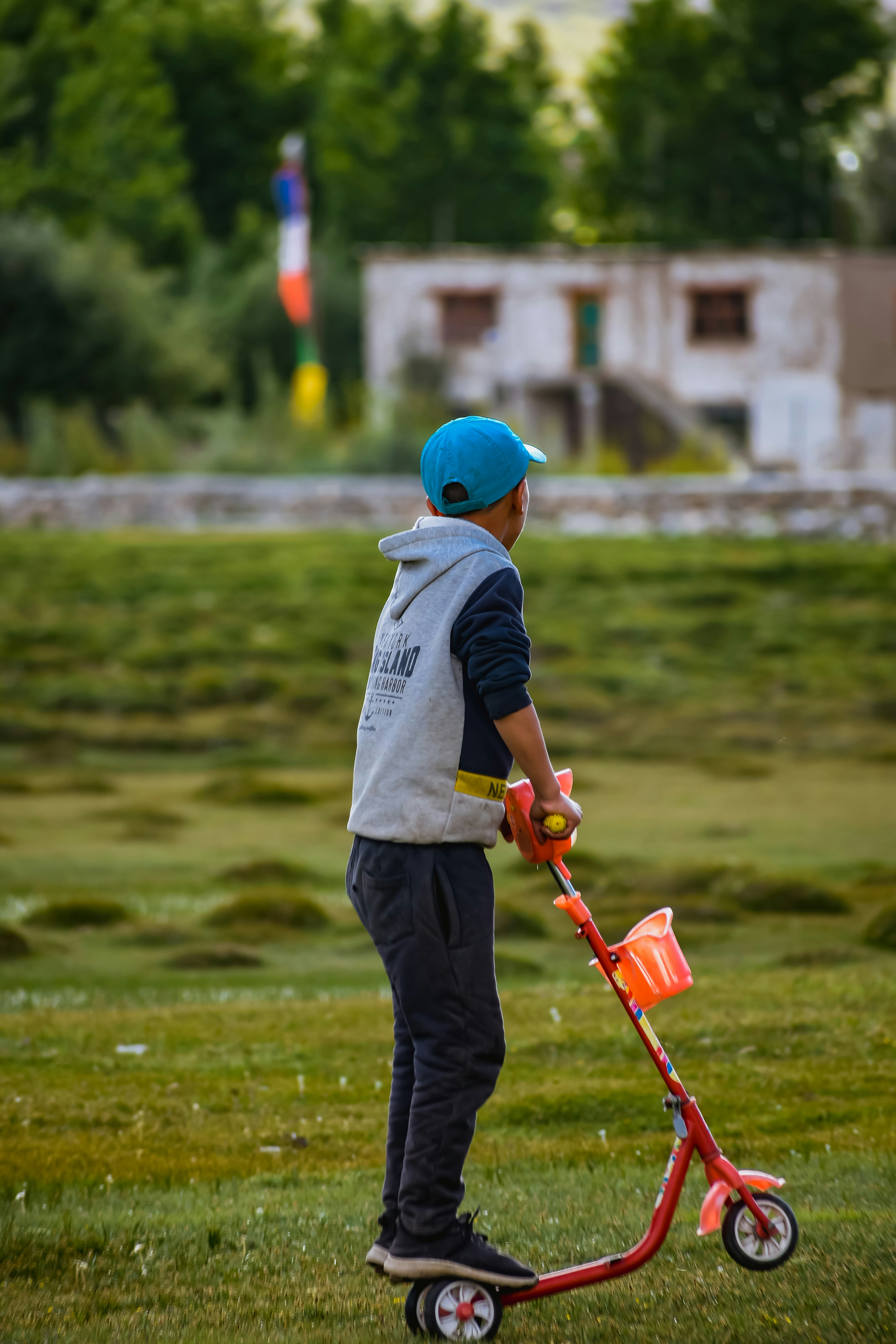 Blue-Capped Rider on a Red Scooter in a Quiet Meadow