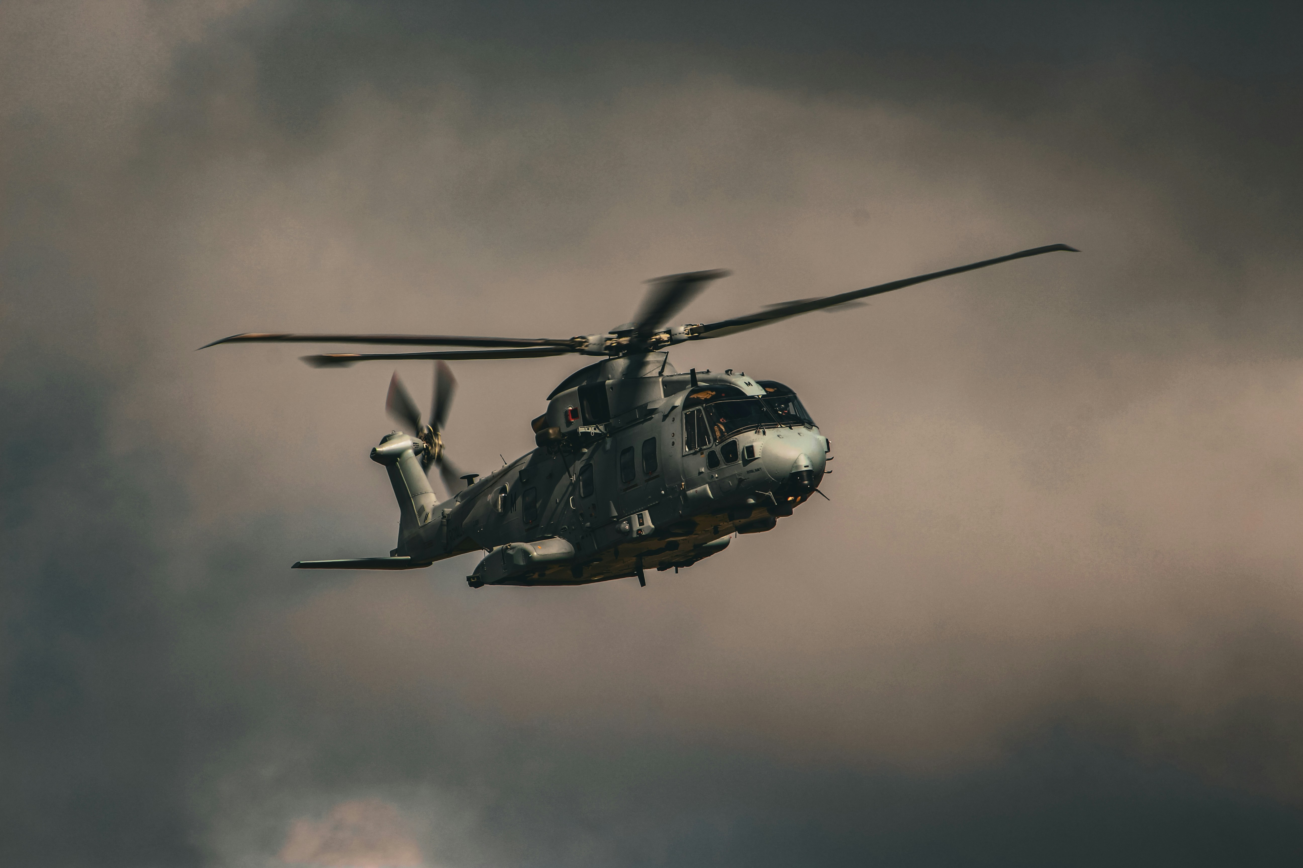 Sleek MH-60 silhouette slicing through storm-lit clouds