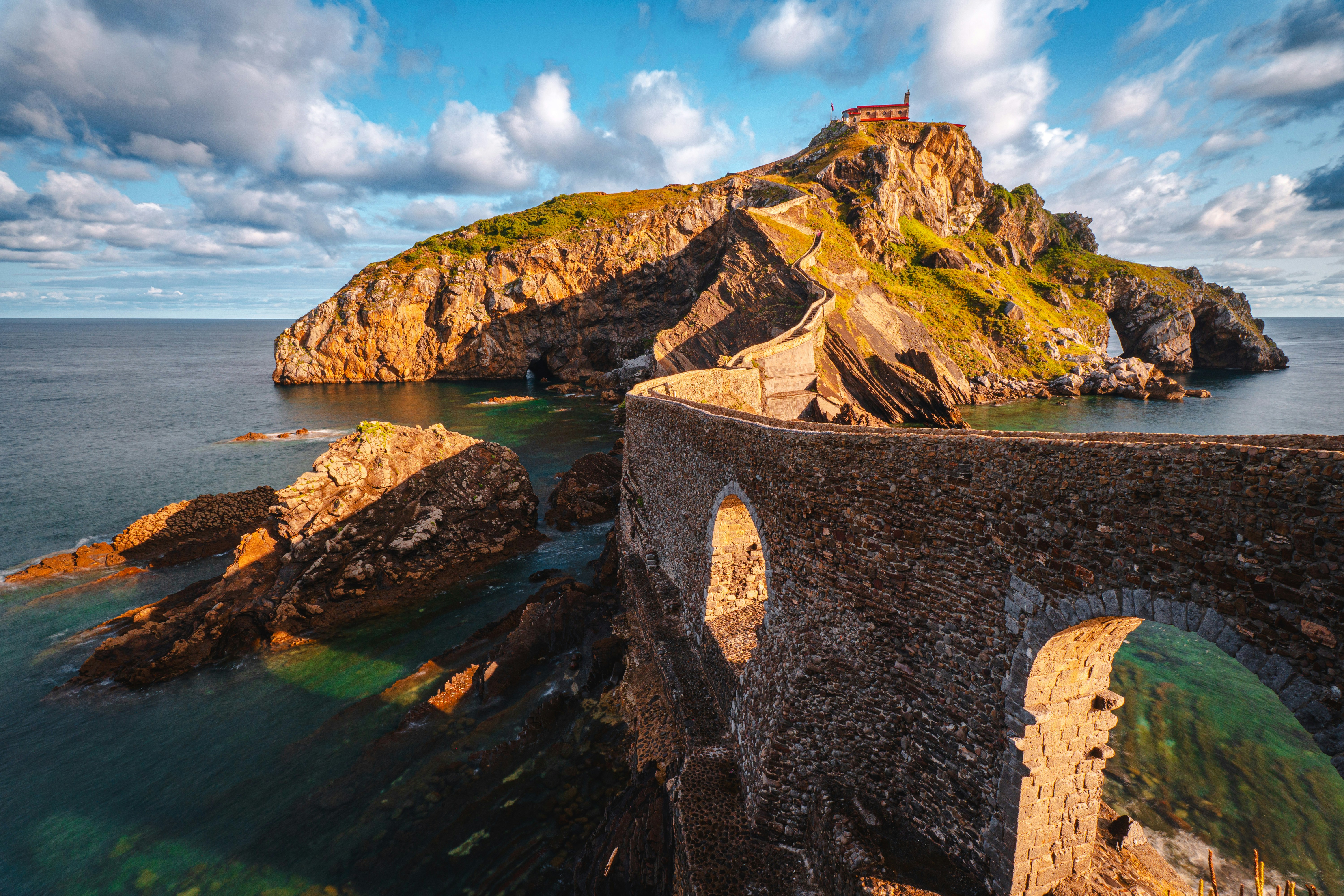 Bridge to the Isle: Sunlit Arch Leading to a Cliffside Fortress