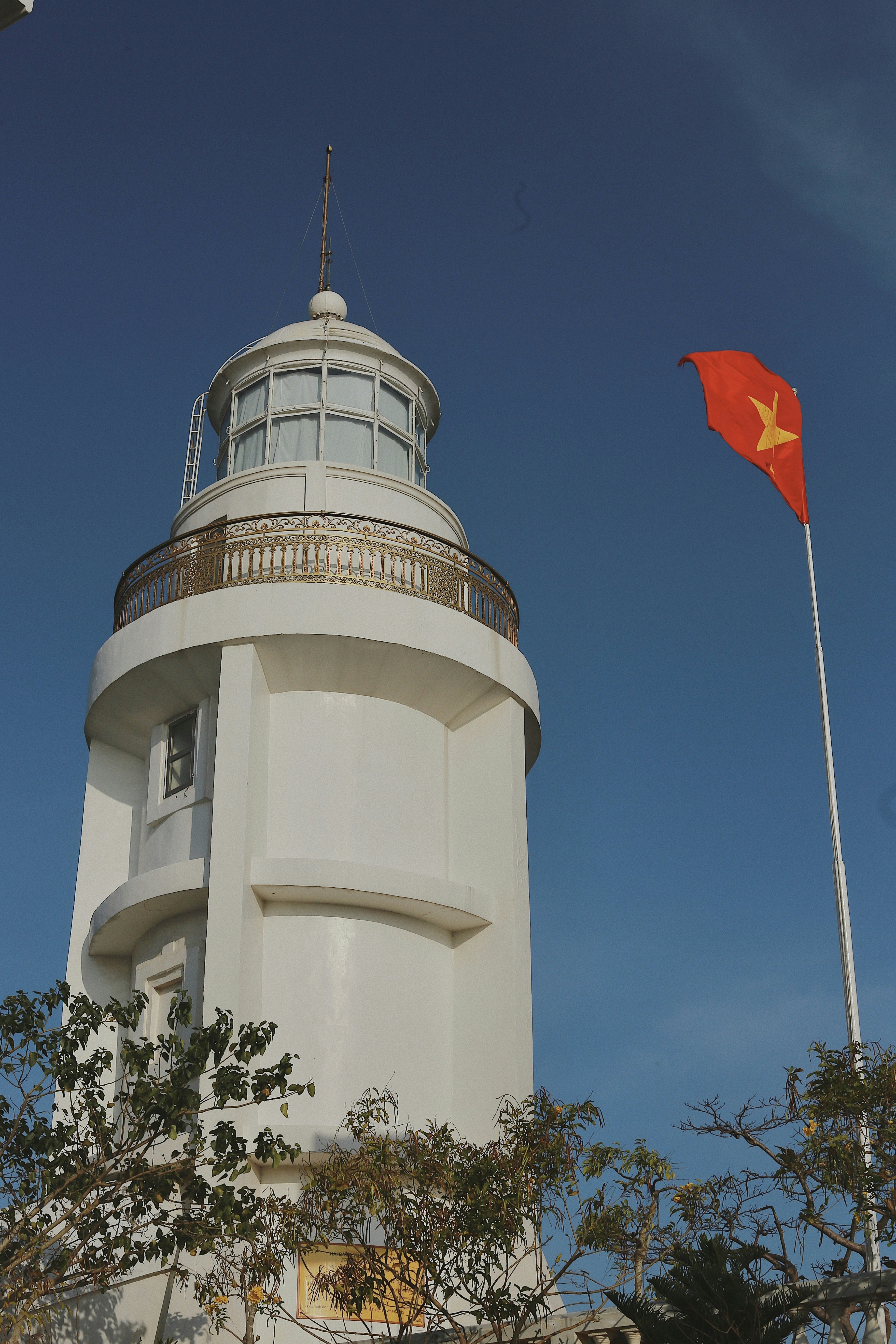 A large white tower with a red flag on top of it photo – Free Ba ria ...