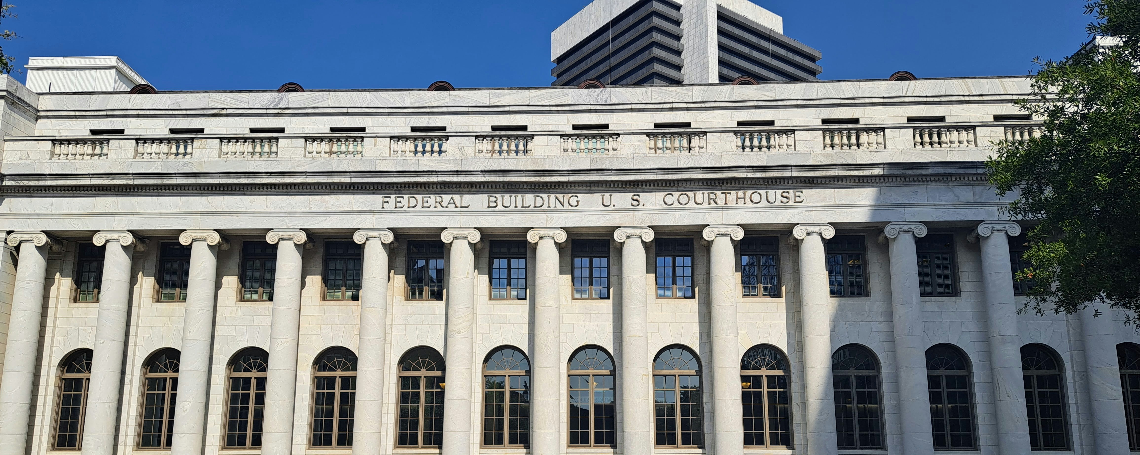 Neoclassical building with tall columns and arched windows beneath a clear blue sky.