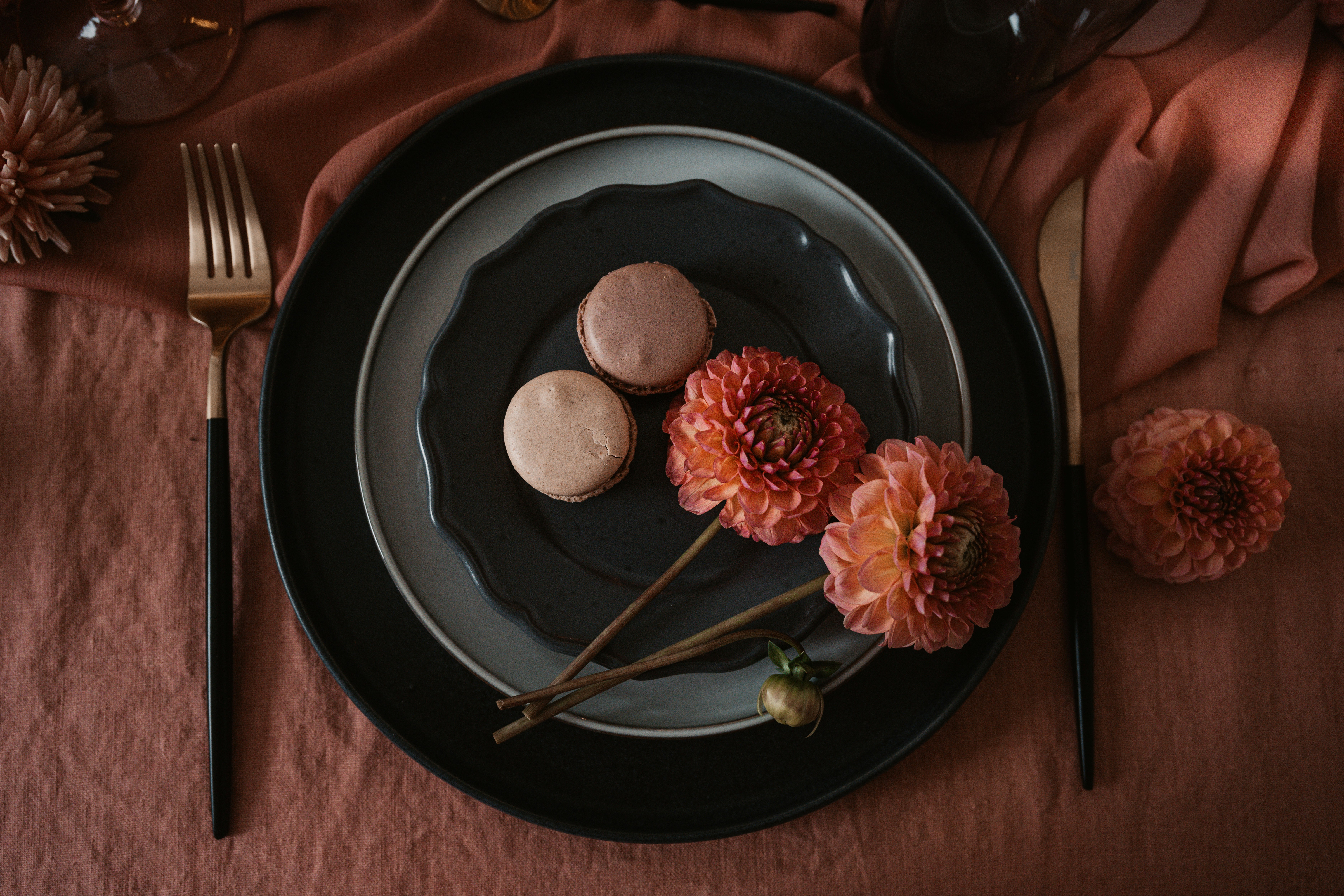 Macaron Duo on a Wine-Red Table, Framed by Coral Dahlias