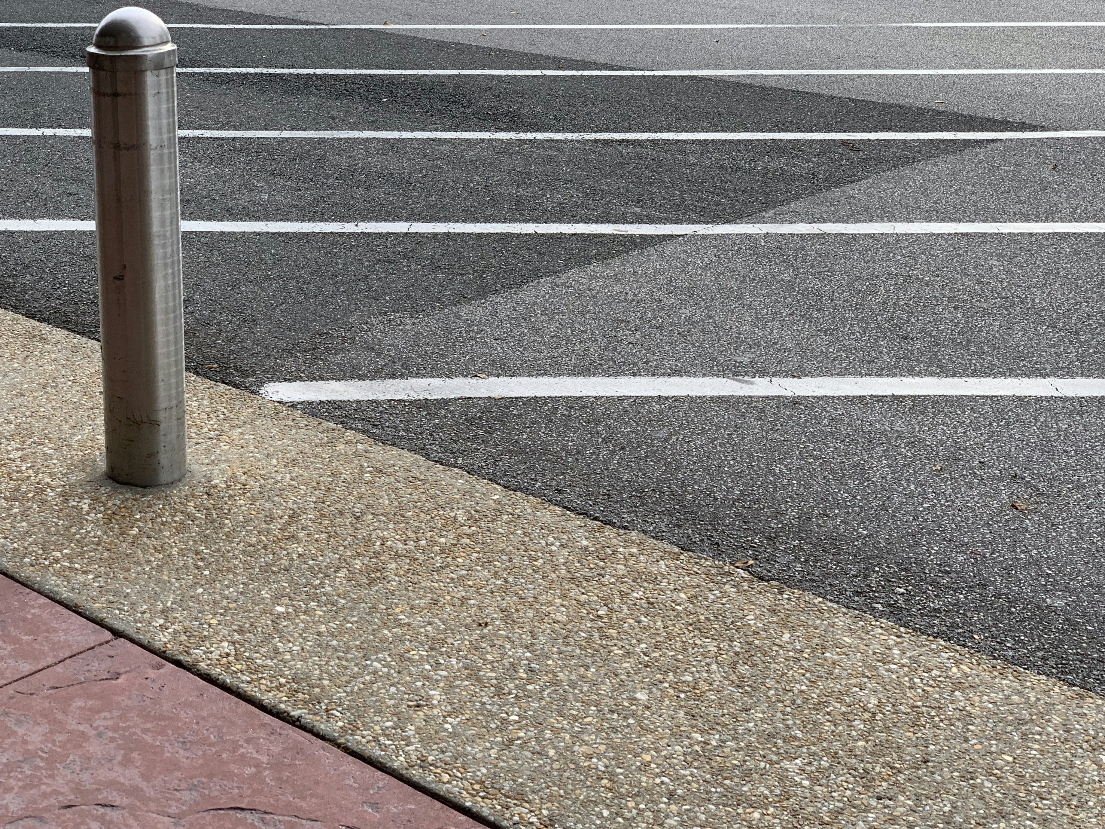 Lonely Bollard Framing the Textured Edge of a Parking Lot