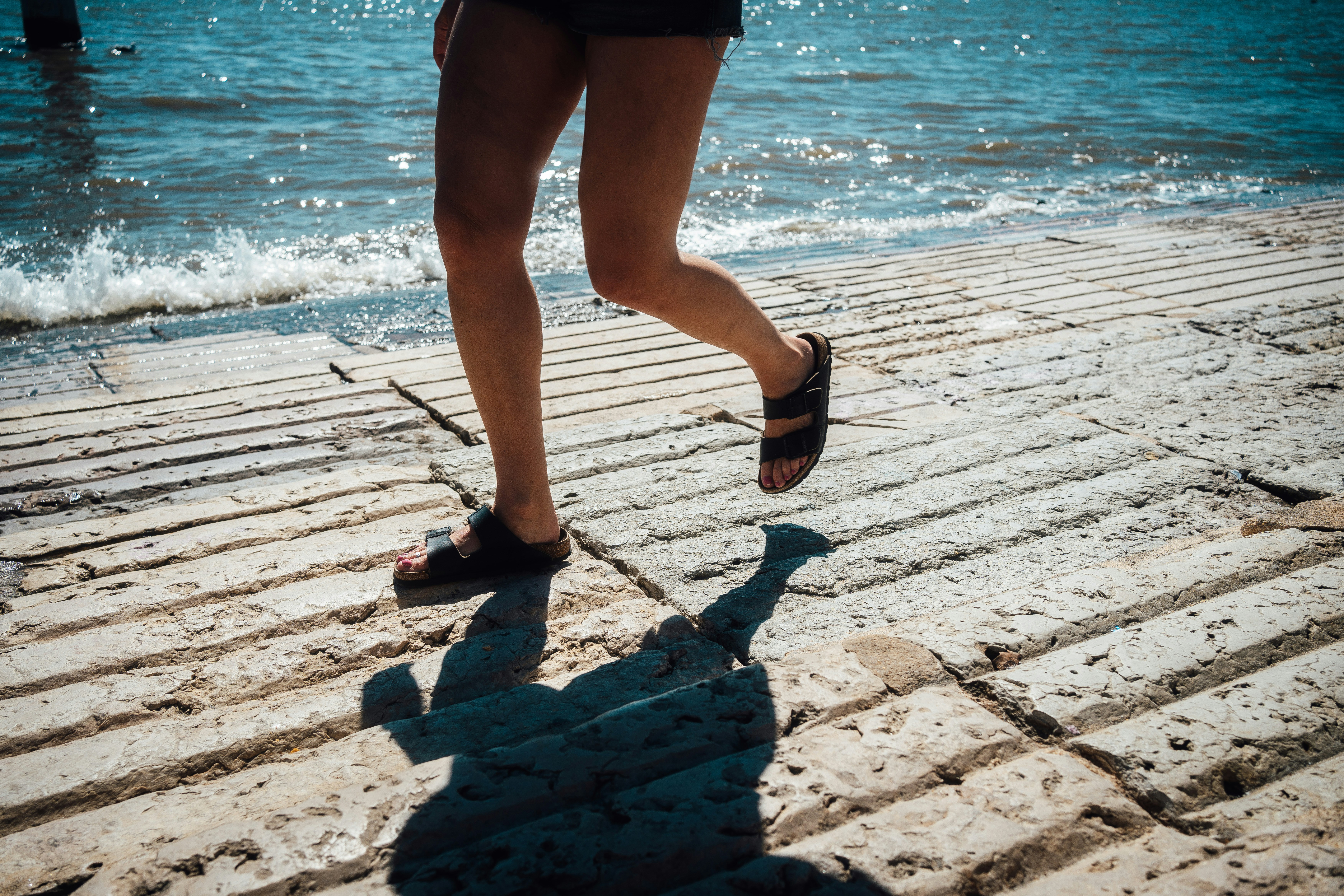 A woman is running on a pier near the water photo – Free Strand Image ...