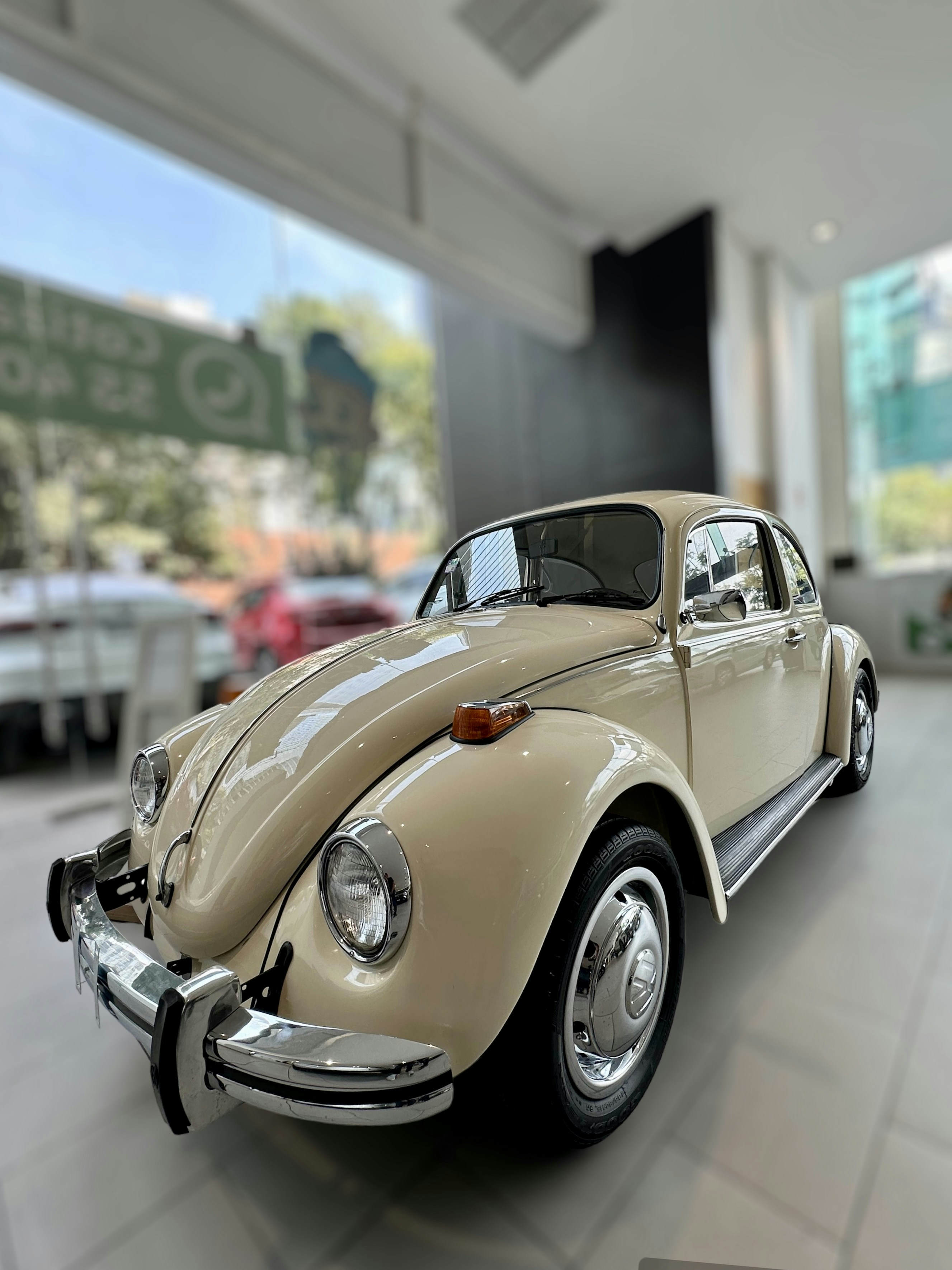 A beige vw bug is parked in a showroom photo – Free Wheel Image on Unsplash