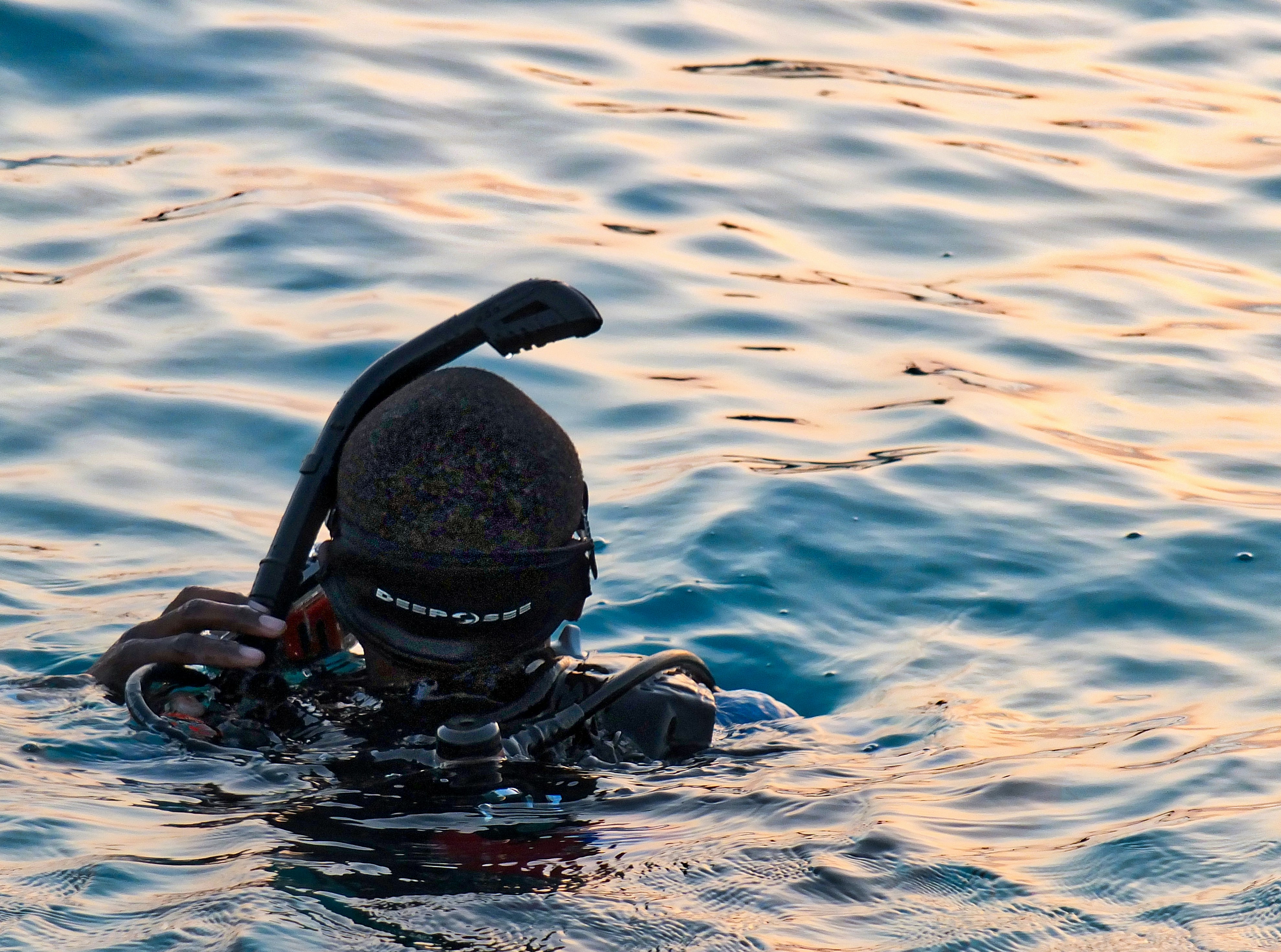 Snorkeler's Silhouette Beneath Sunset Ripples