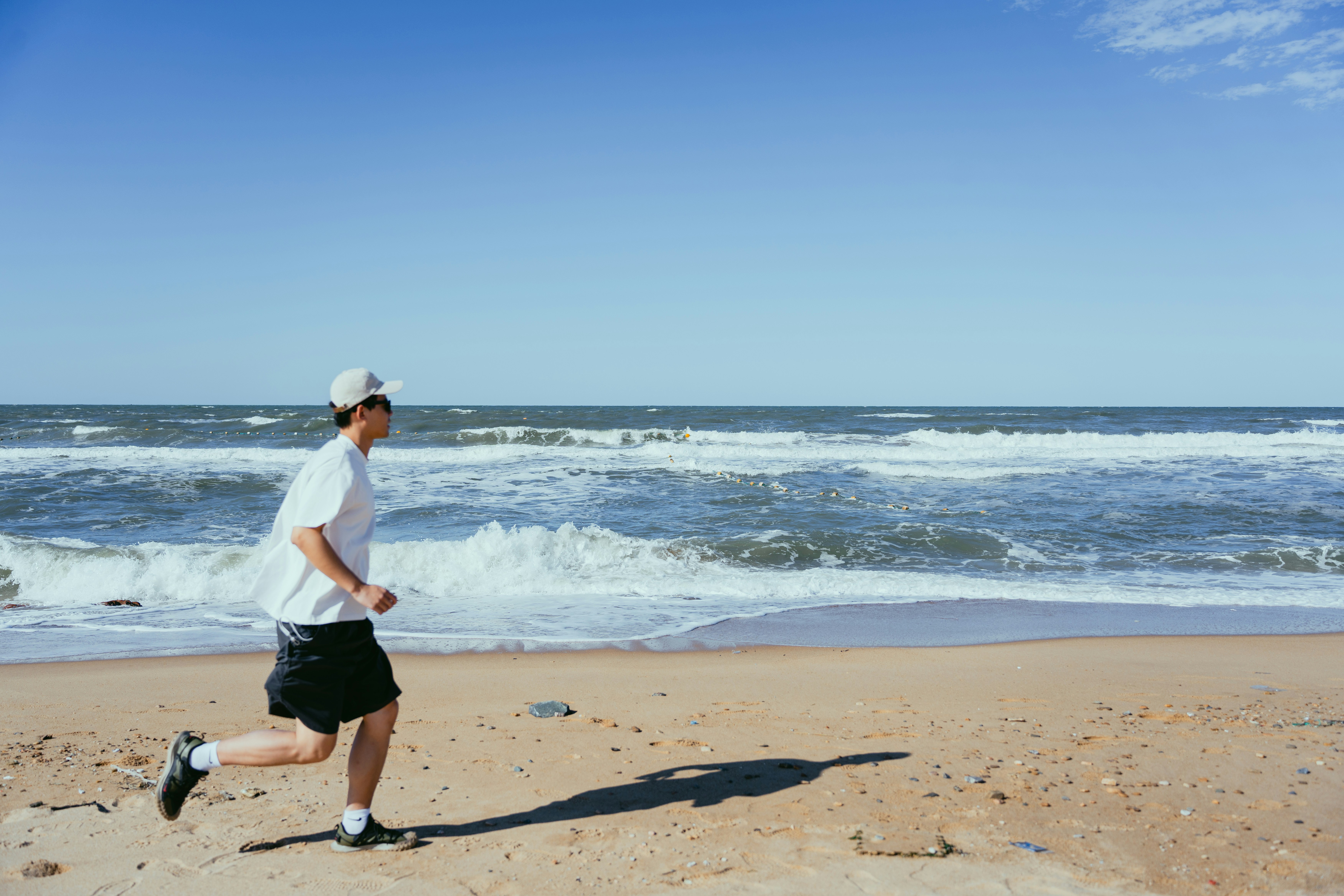 A man running on a beach near the ocean photo – Free Beachwear Image on ...