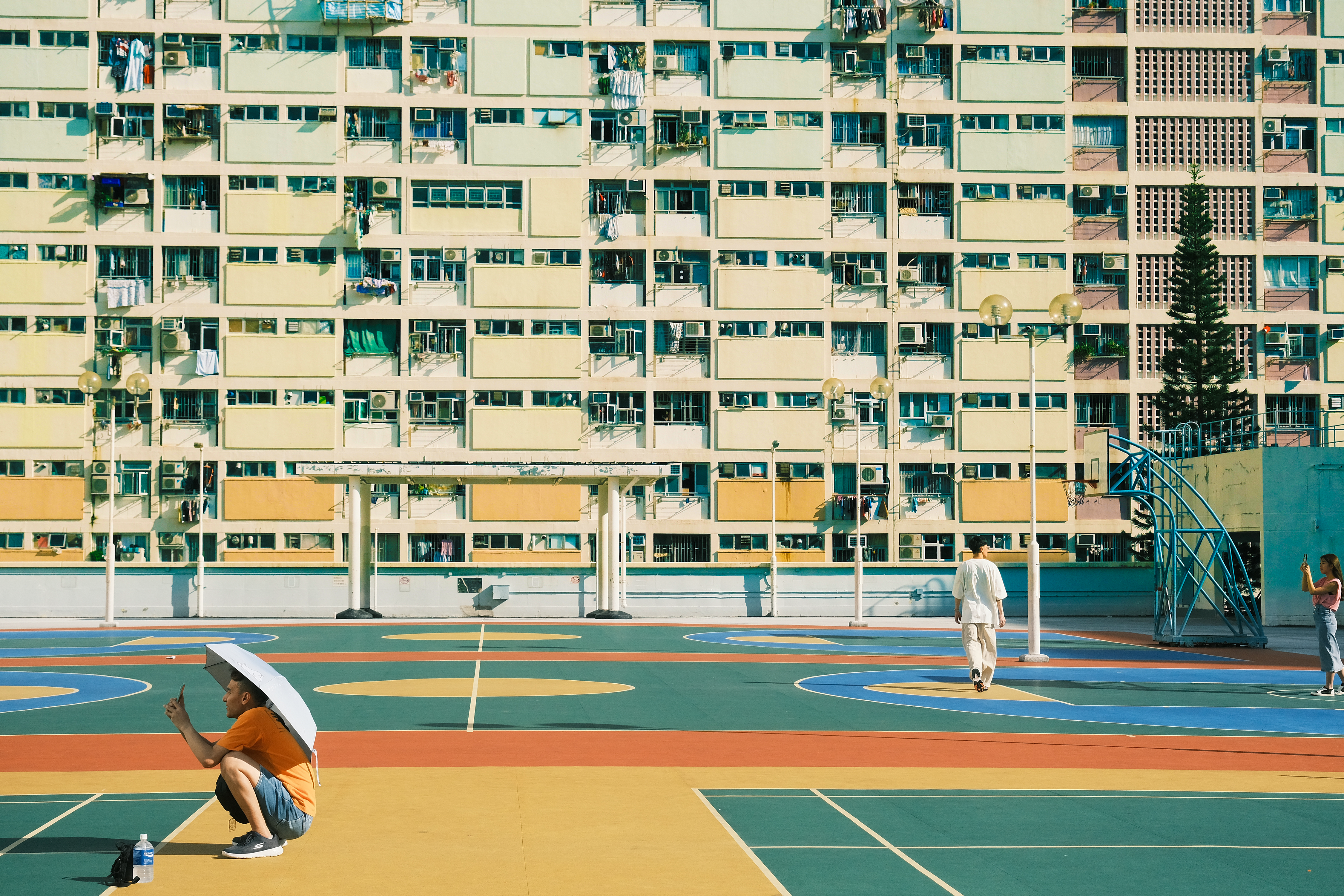 A person sitting on a basketball court holding an umbrella photo – Free ...