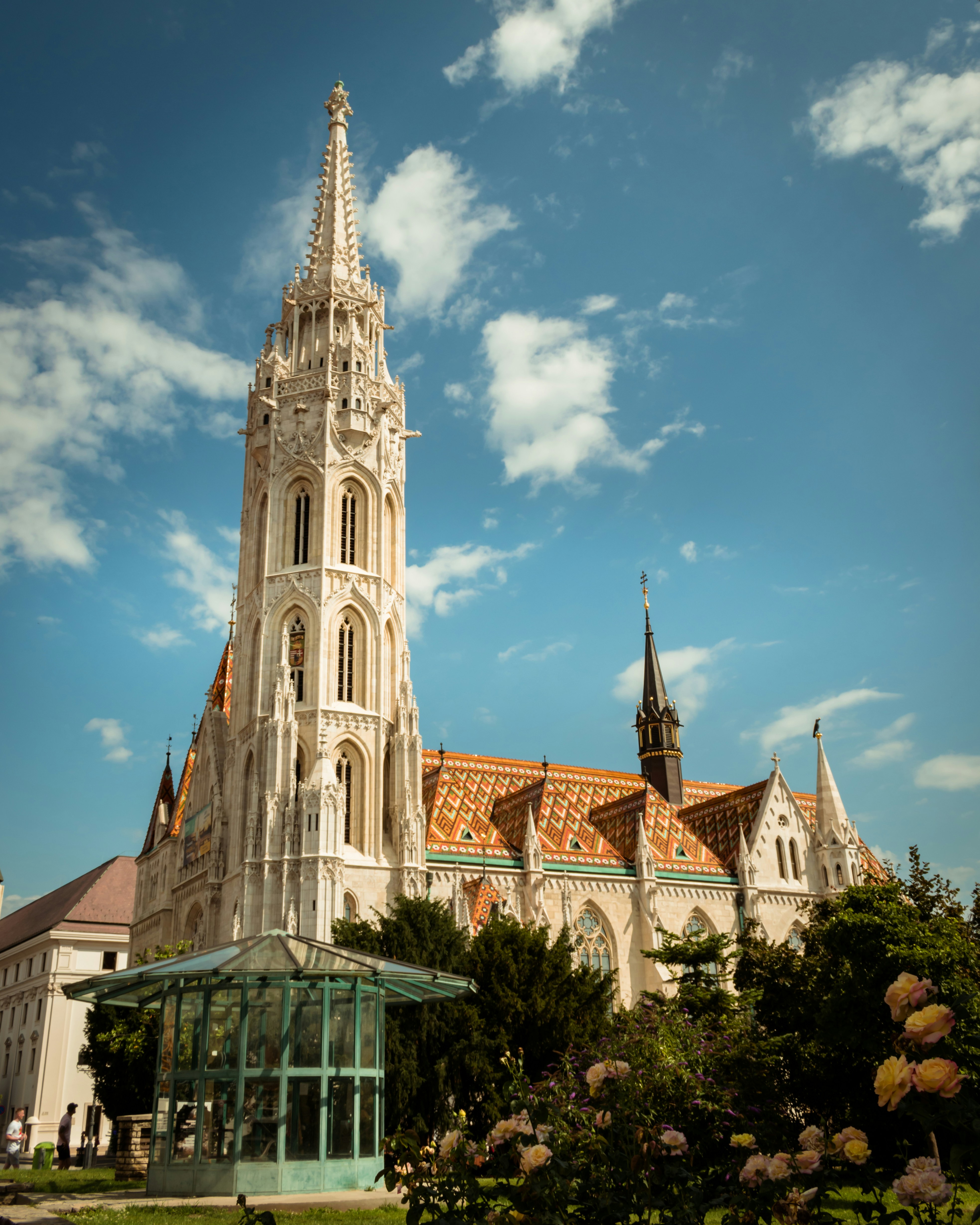 Spire and Sky: A Sunlit Gothic Tower Over a Tile-Roofed Church