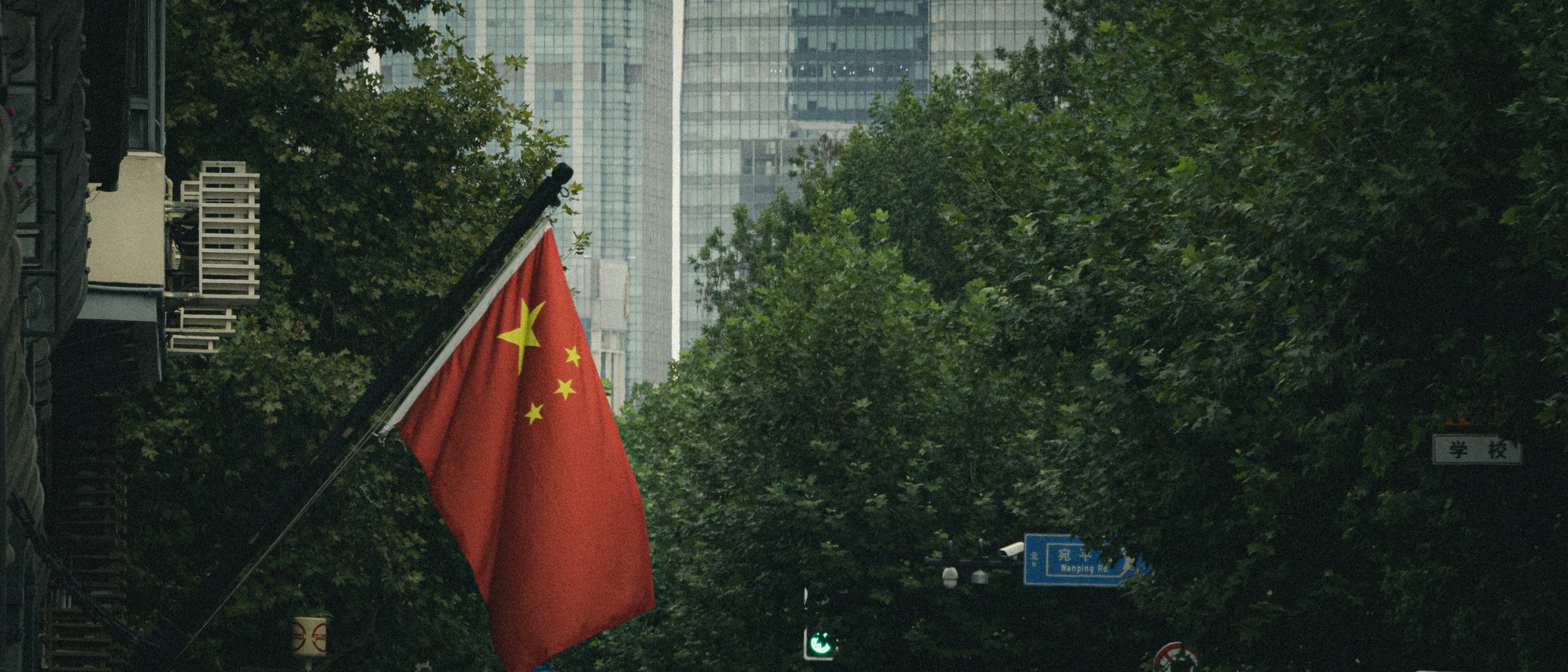 A chinese flag flying in the wind on a city street photo – Free Light ...