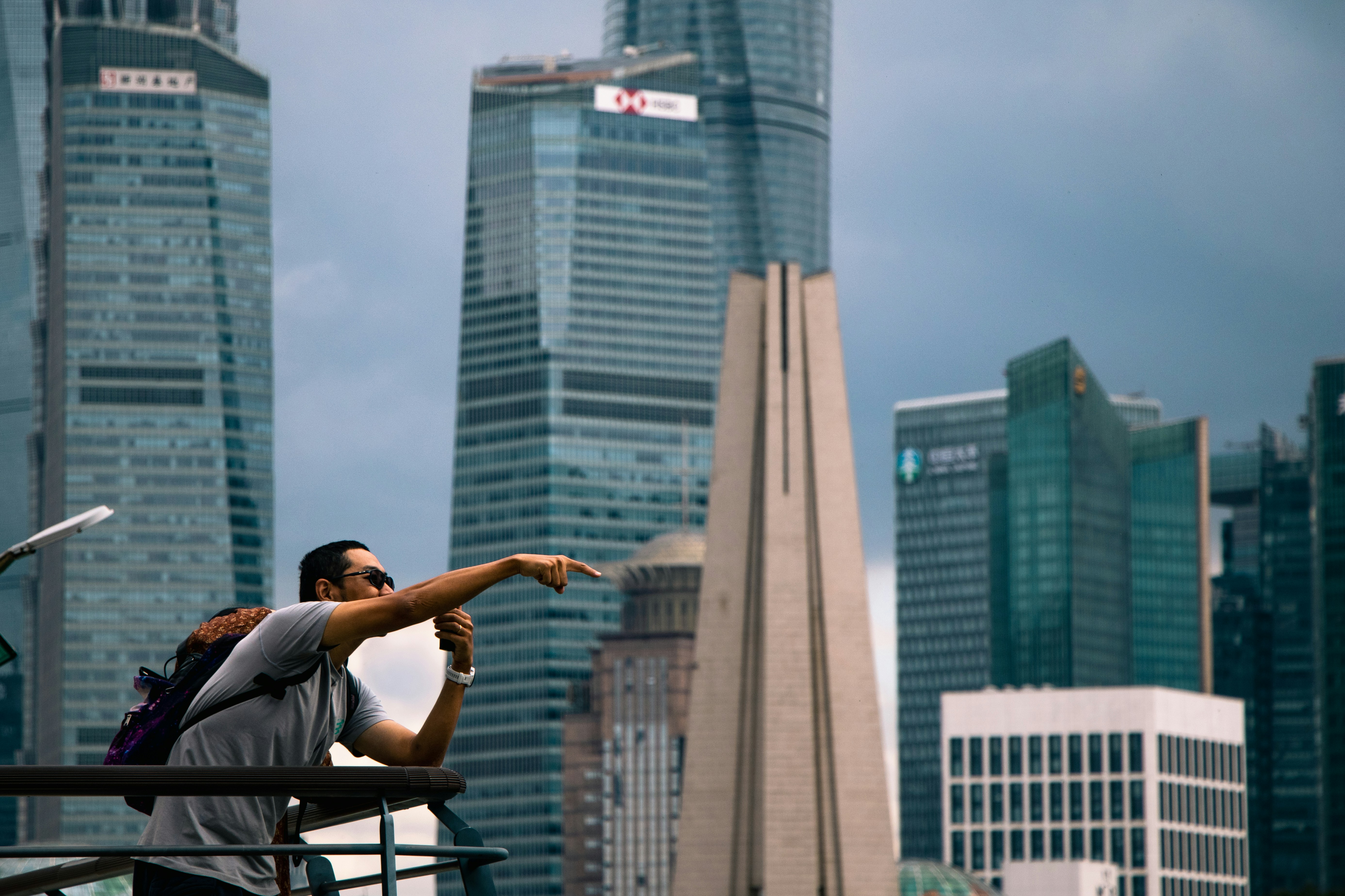 A man pointing at something in front of some tall buildings photo ...