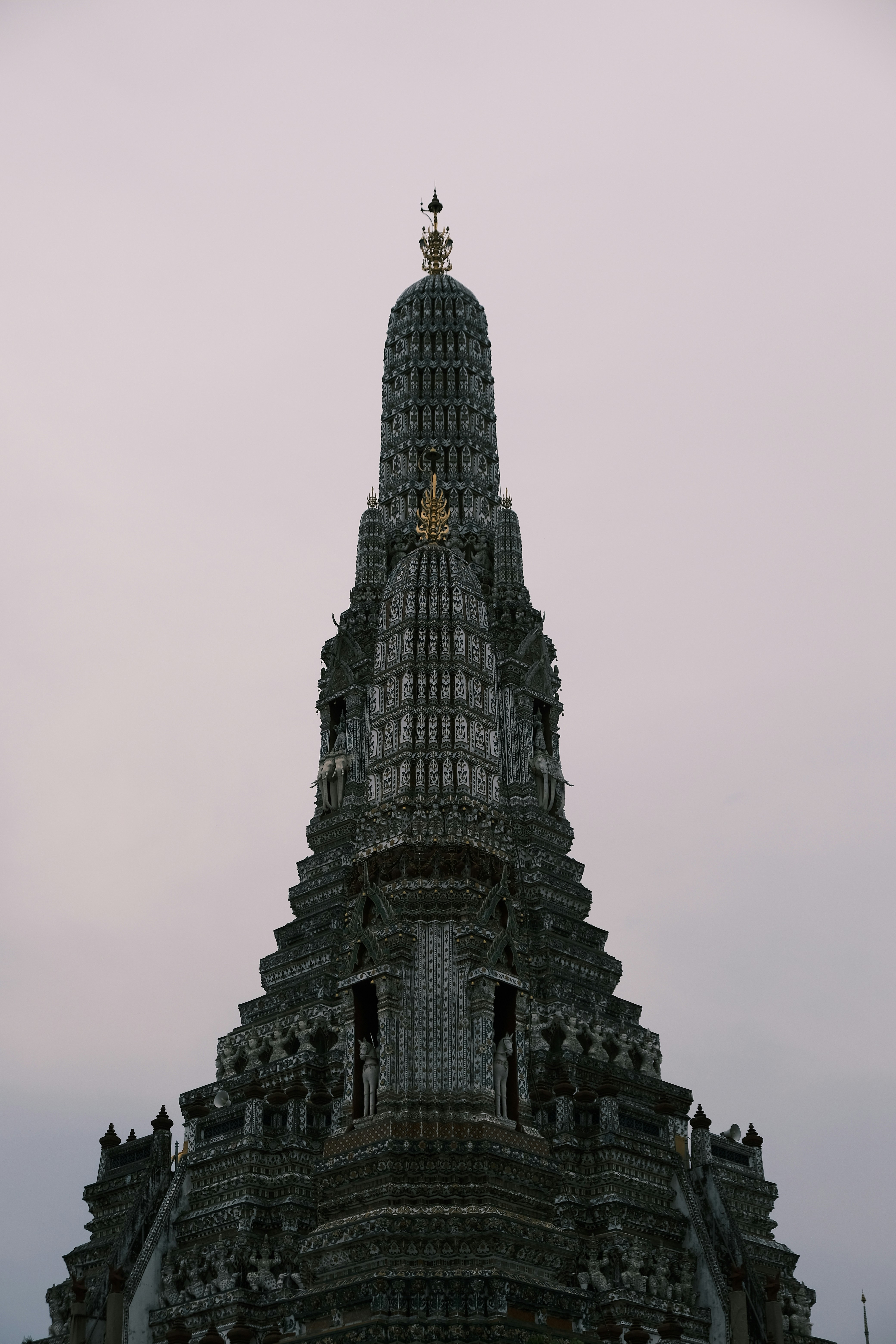 Central Prang Ascending: Intricate Stone Spire Reaching a Pale Sky
