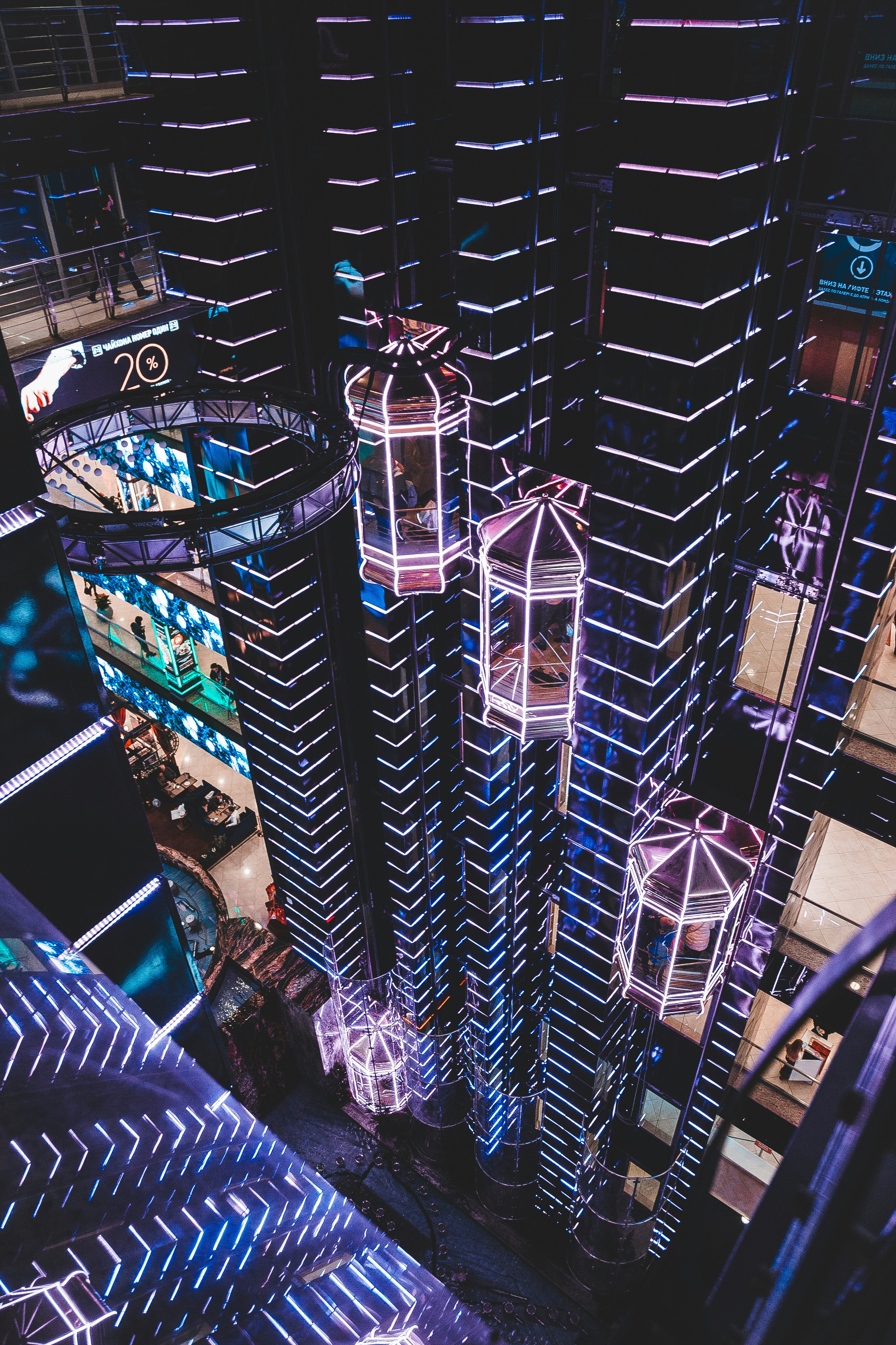 Glass elevators adorned with vibrant neon lights inside a modern building.