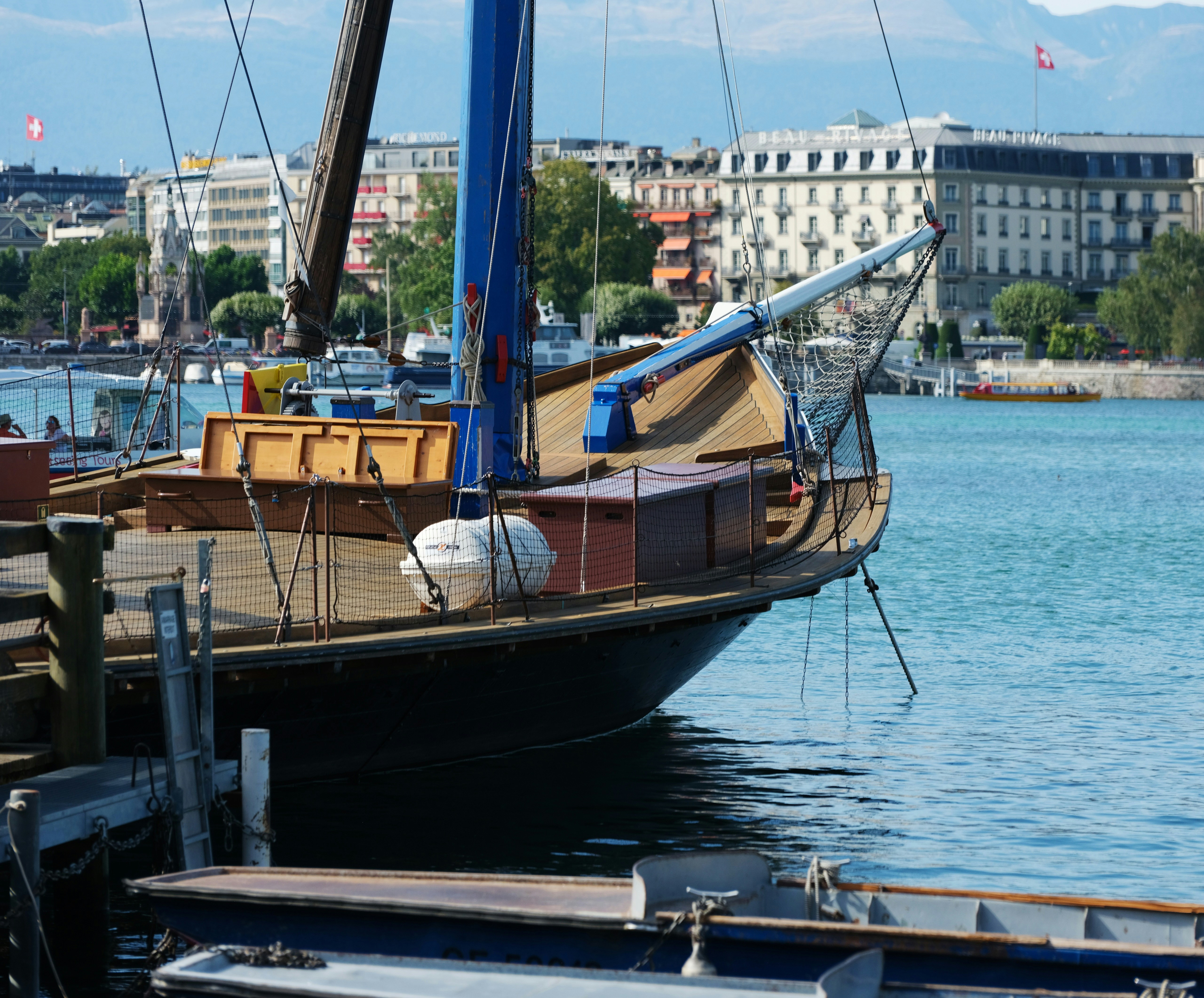 Blue-Mast at Rest: A Wooden Sailboat Nestled by a Calm Harbor
