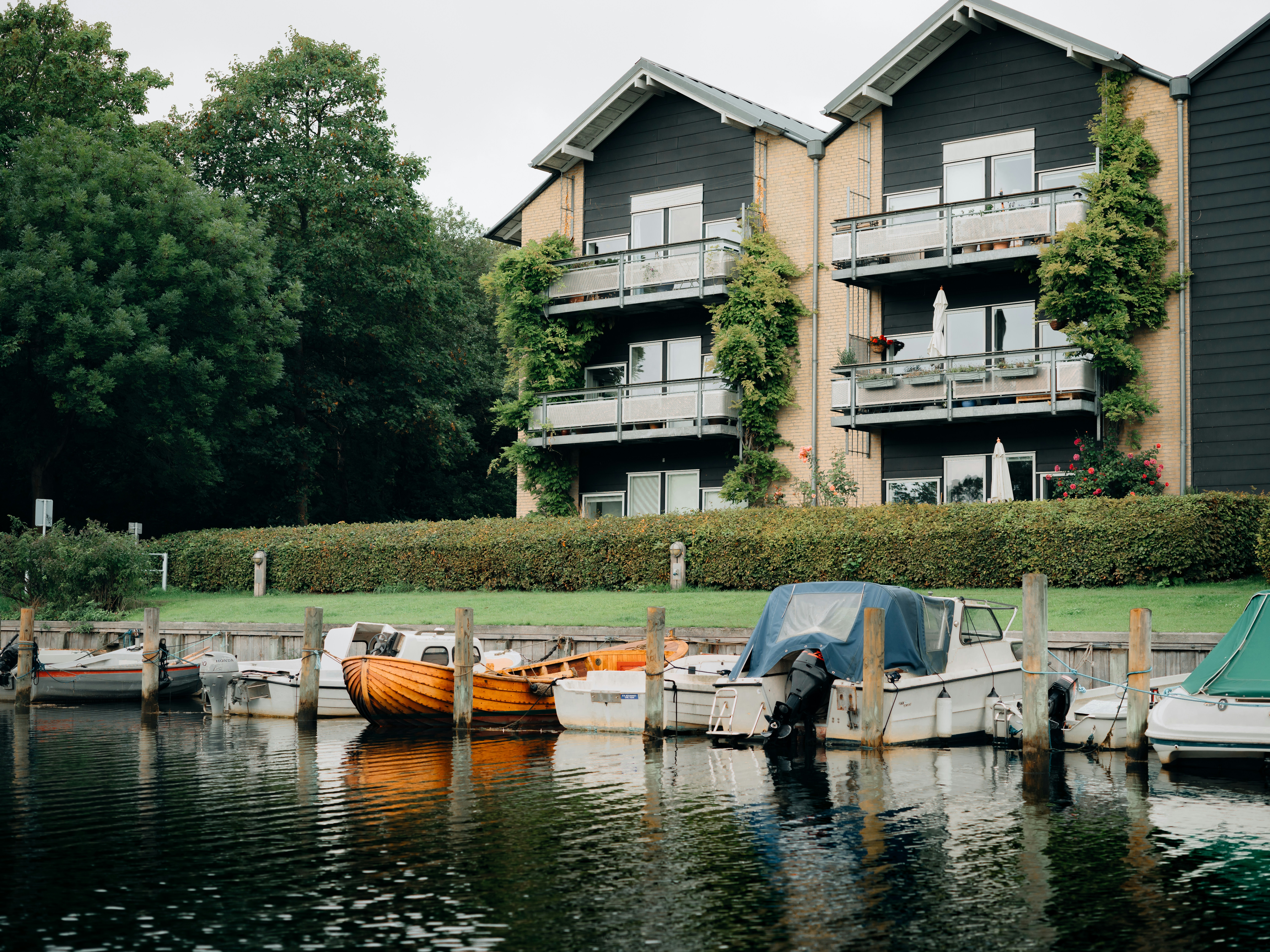Amber Skiff Resting Along a Calm Riverside Between Ivy-Clad Balconies