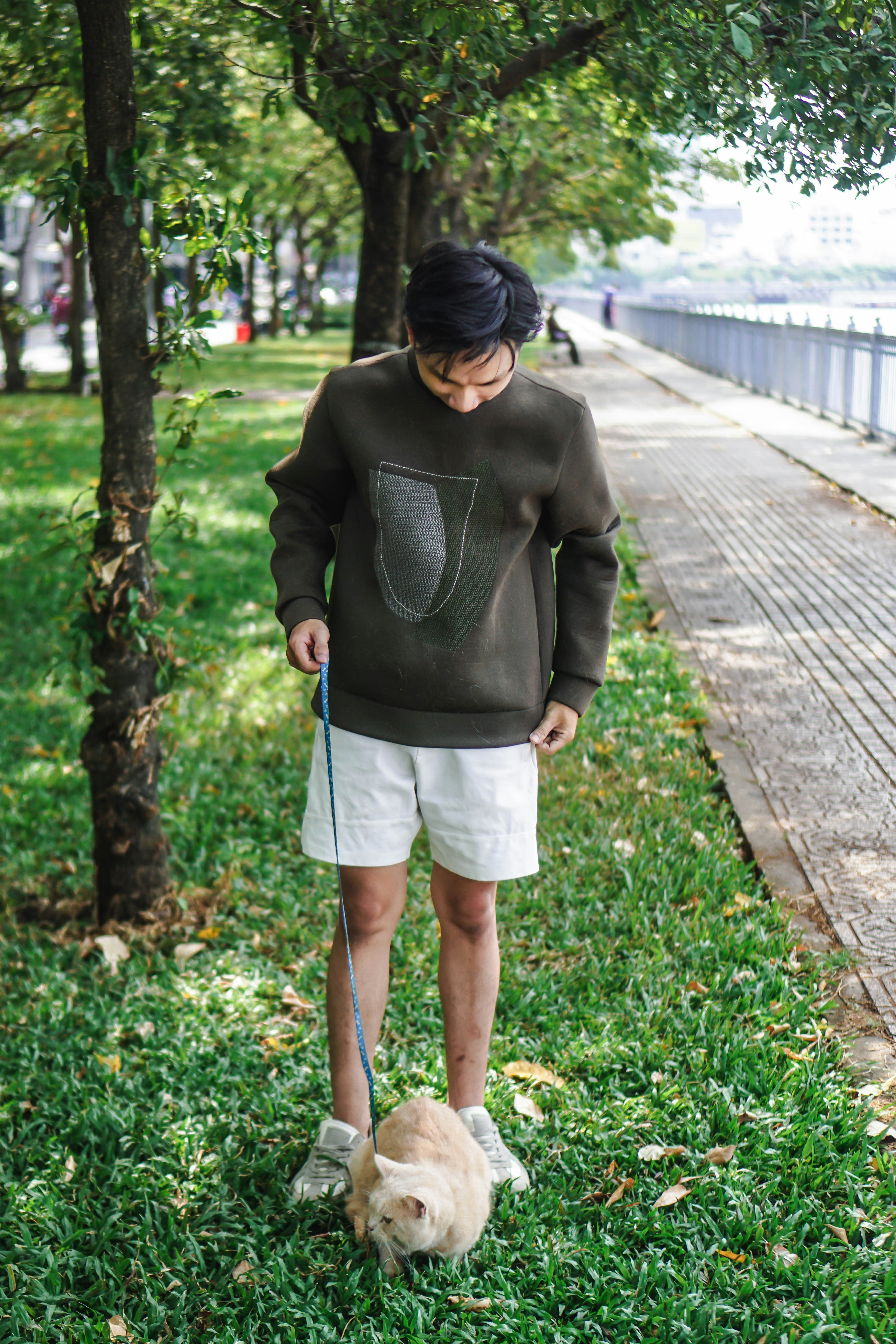 Riverside Quiet: A Man in Olive Sweater with a Fluffy Dog During a Park Stroll