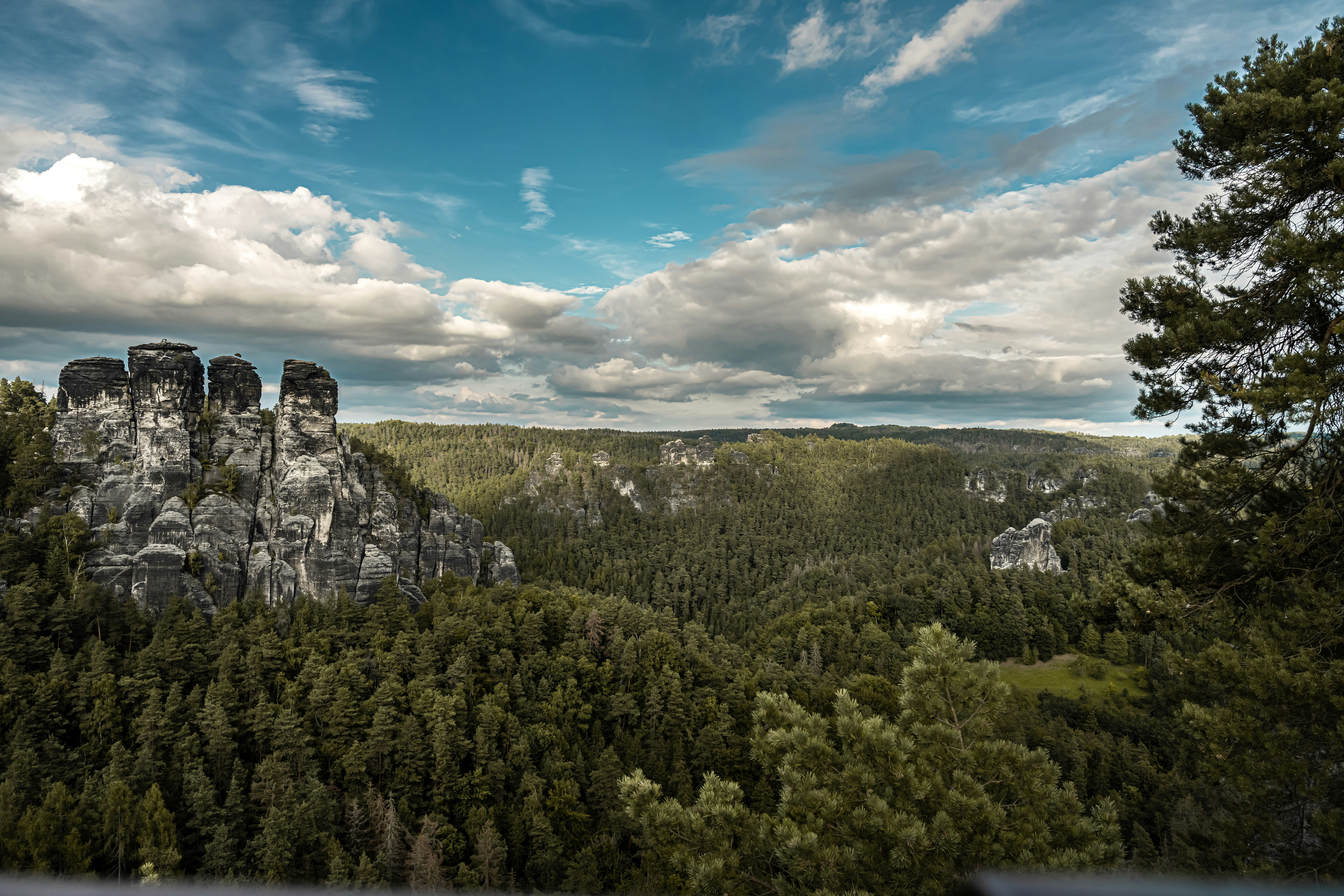 Stone Sentinels Over a Verdant Valley Beneath a Cloud-Dusted Sky