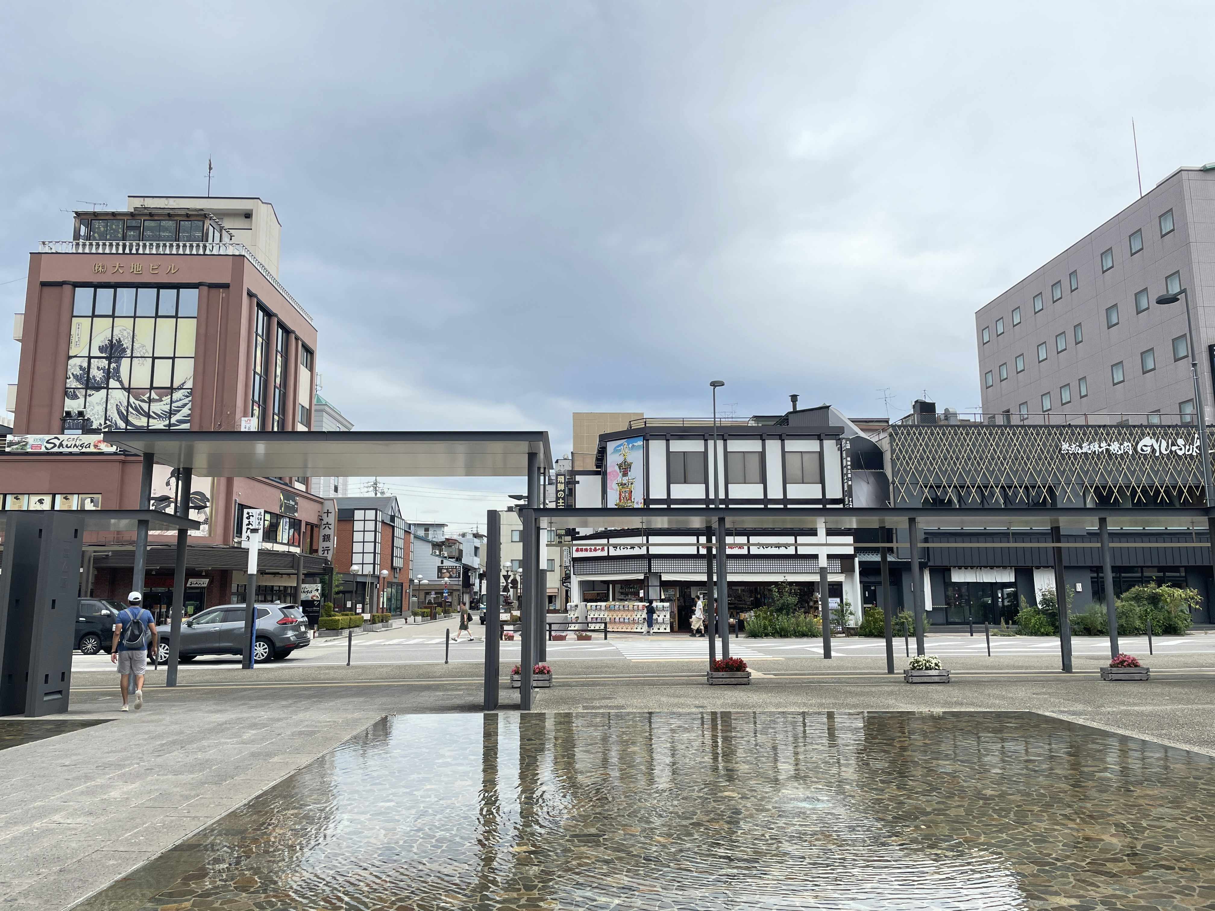 A city square with a fountain and people walking on the sidewalk photo ...