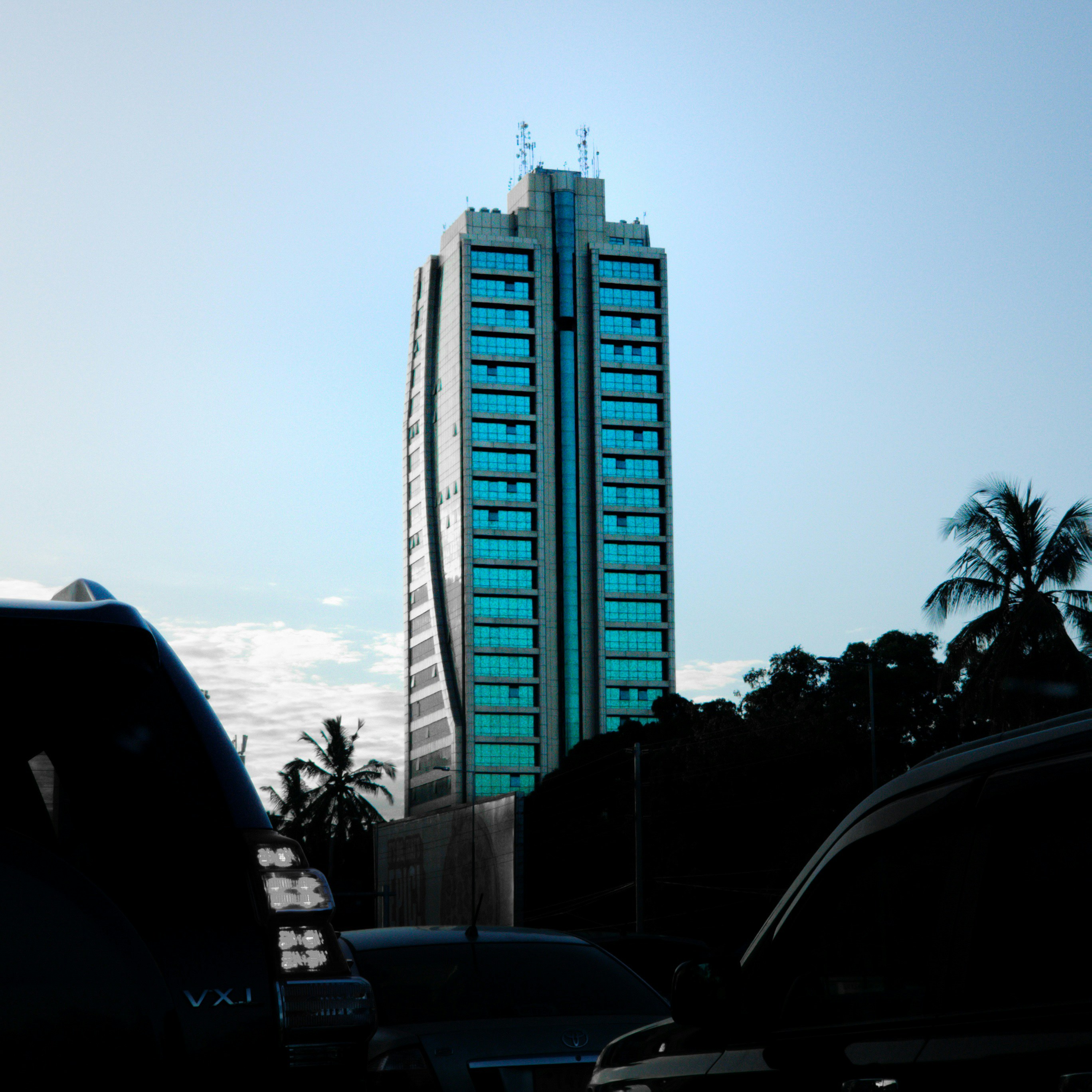 Azure Glass Tower Rising Over Palm-Shadowed Foreground