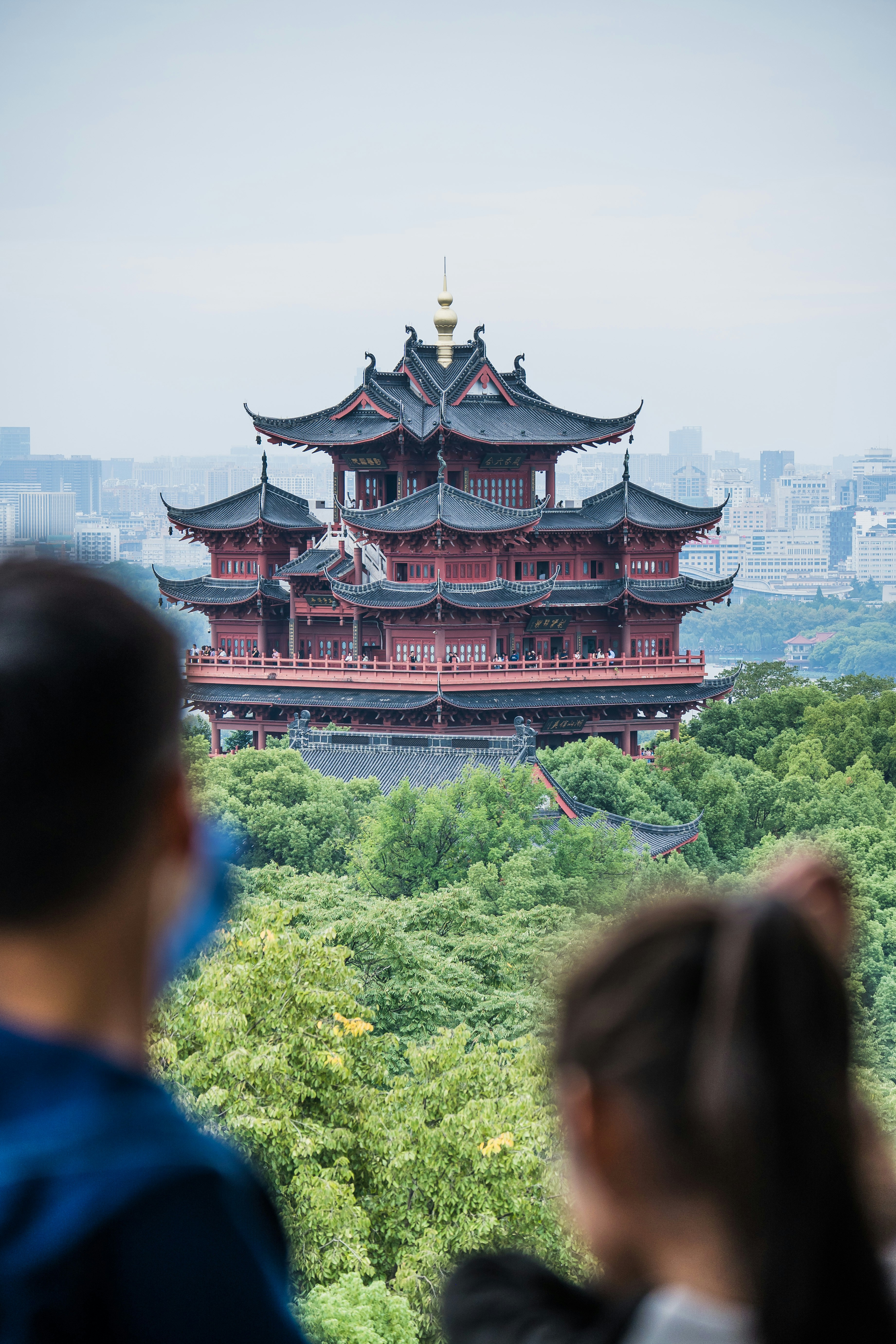 pagoda among pines: a distant, layered temple rises above treeline with blurred visitors in the foreground