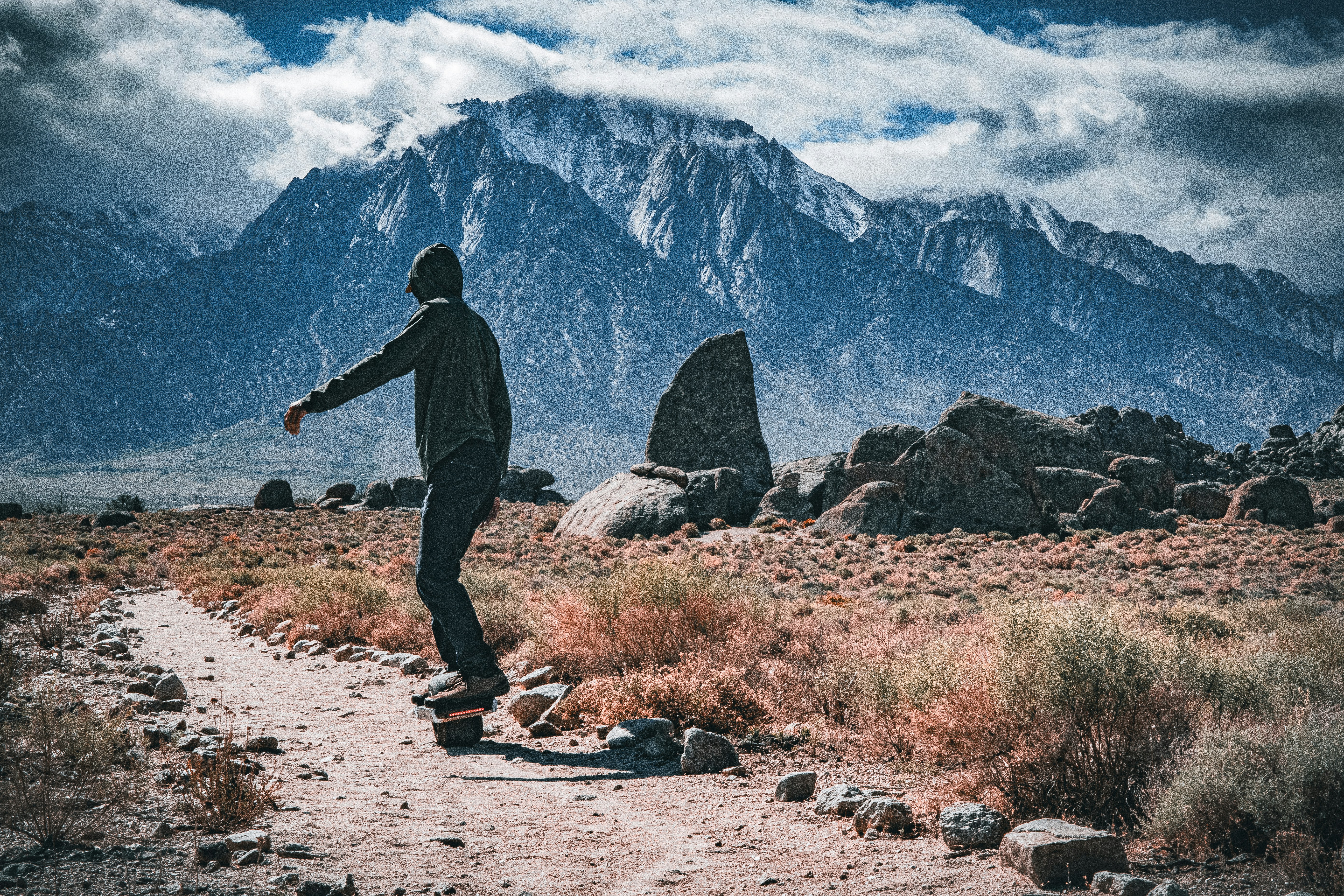 Desert Spine: Skateboarder on a Dusty Trail Beneath Granite Giants