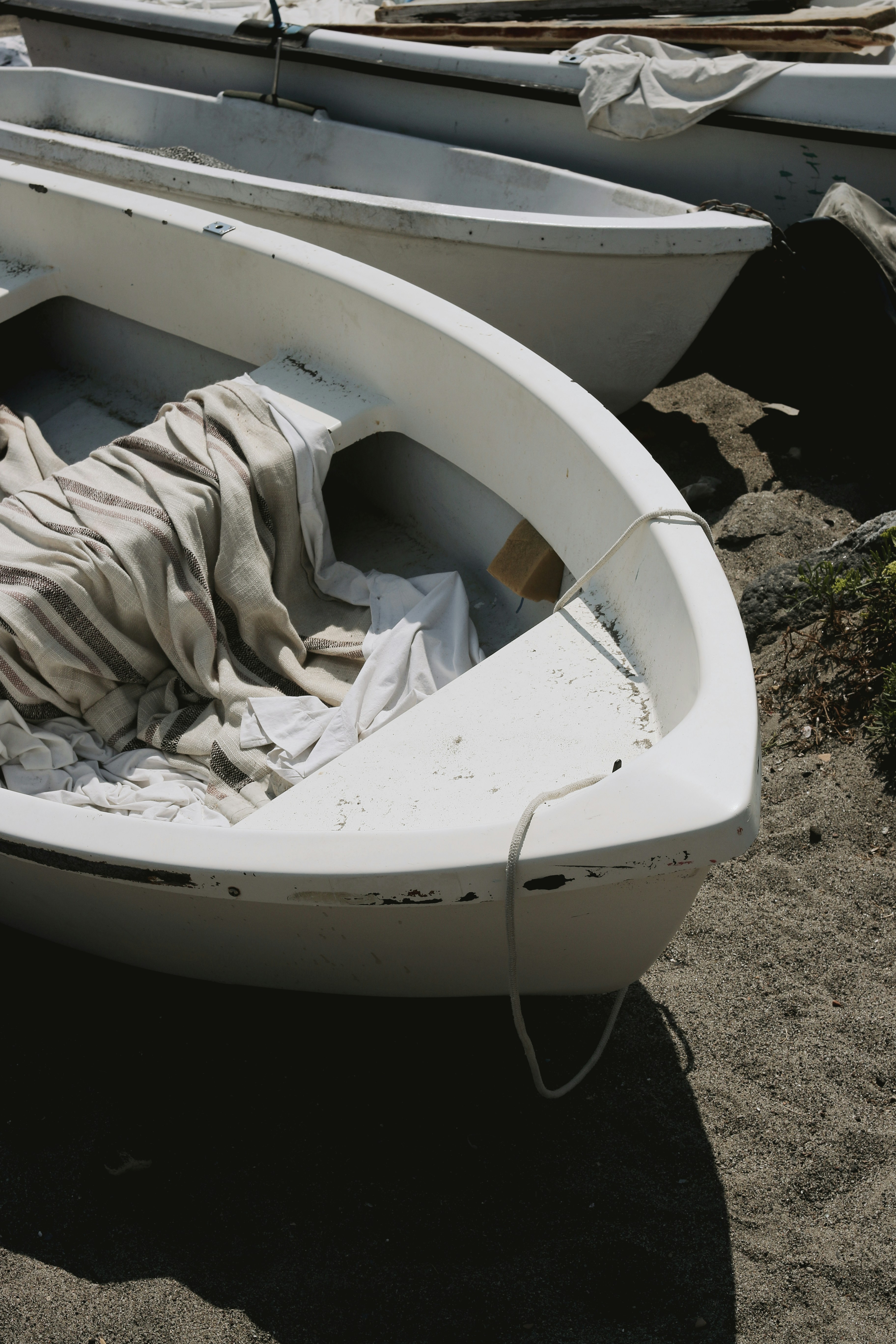 Sunlit Dinghy Interiors on a Rocky Shore