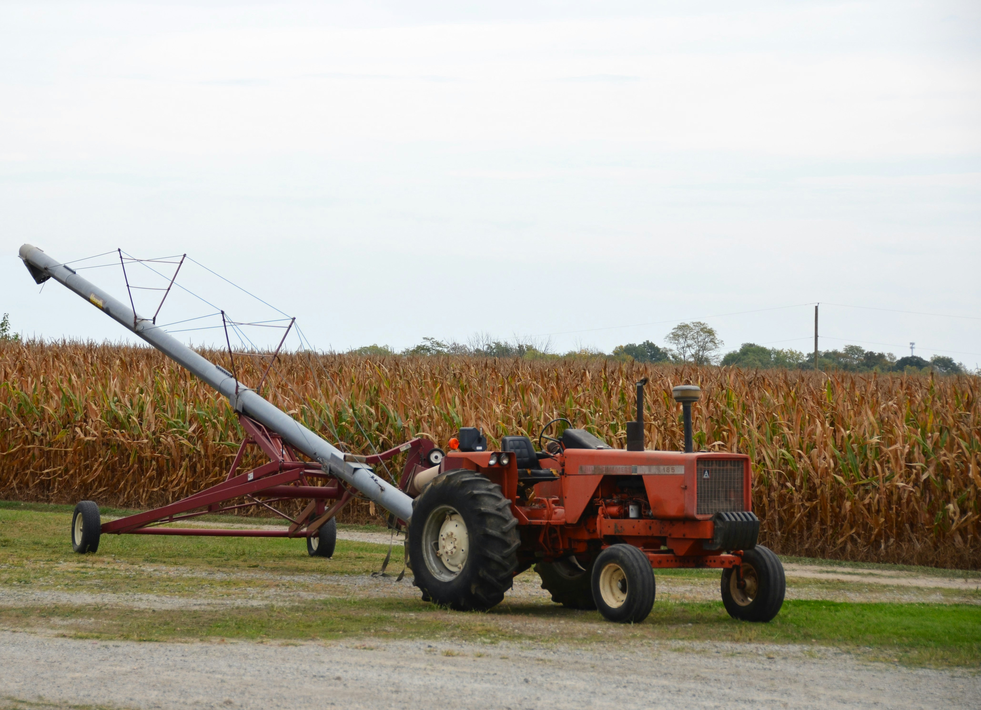 A red tractor pulling a large metal pole photo – Free Grass Image on ...