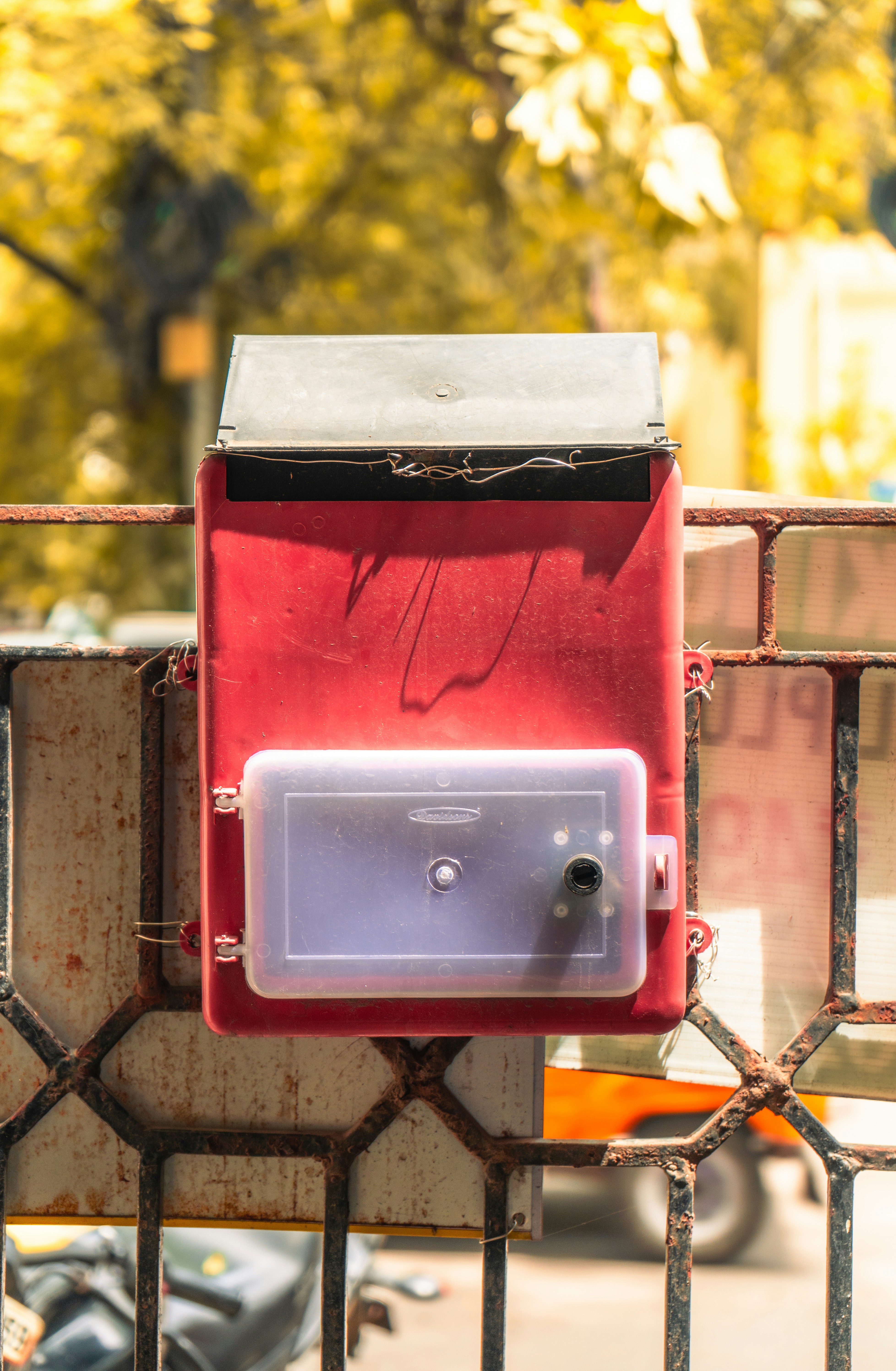 Red mailbox grafted to rusted railing under autumn glow