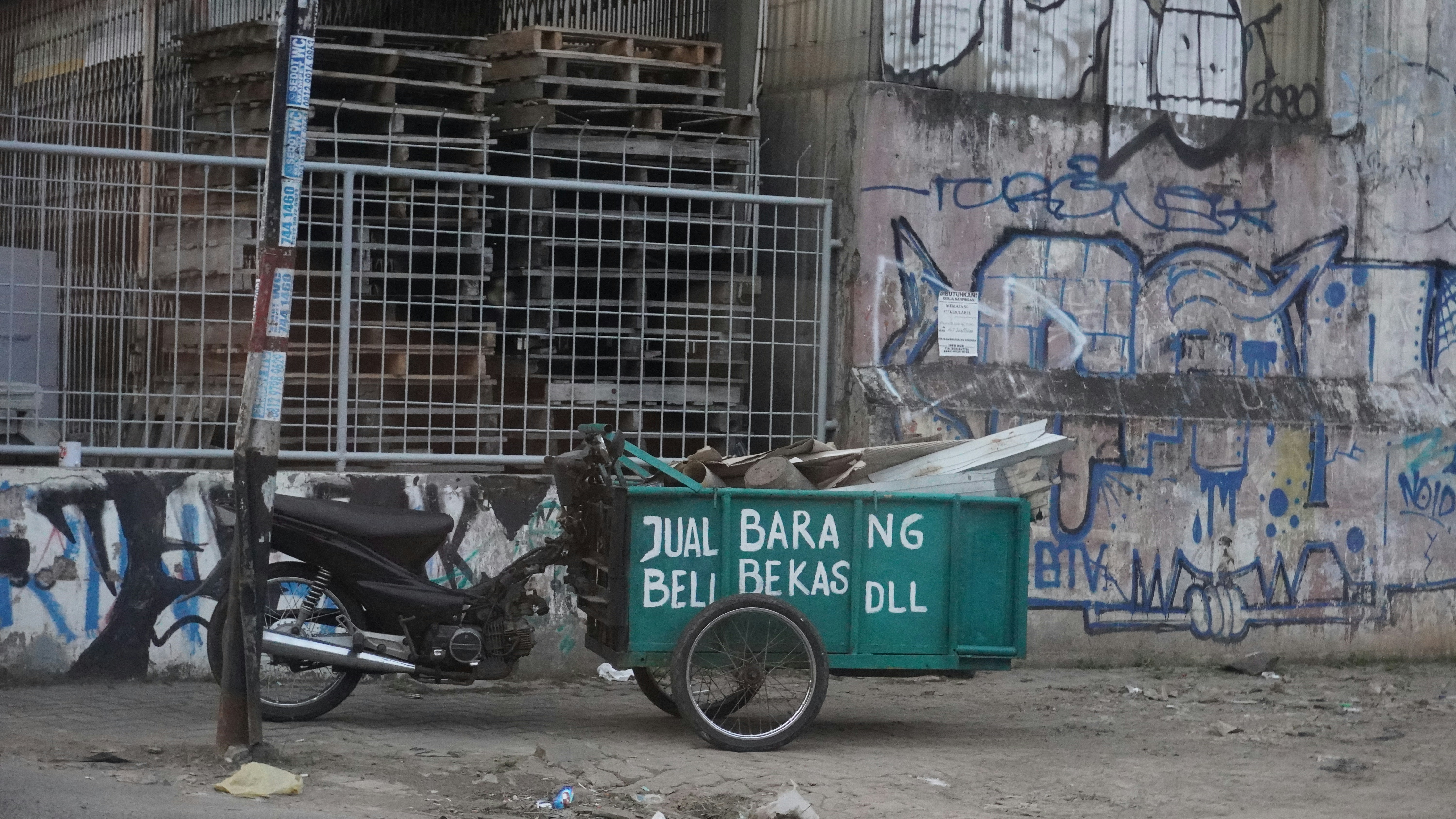 Motorized cart filled with second-hand goods against a graffiti-covered urban wall.