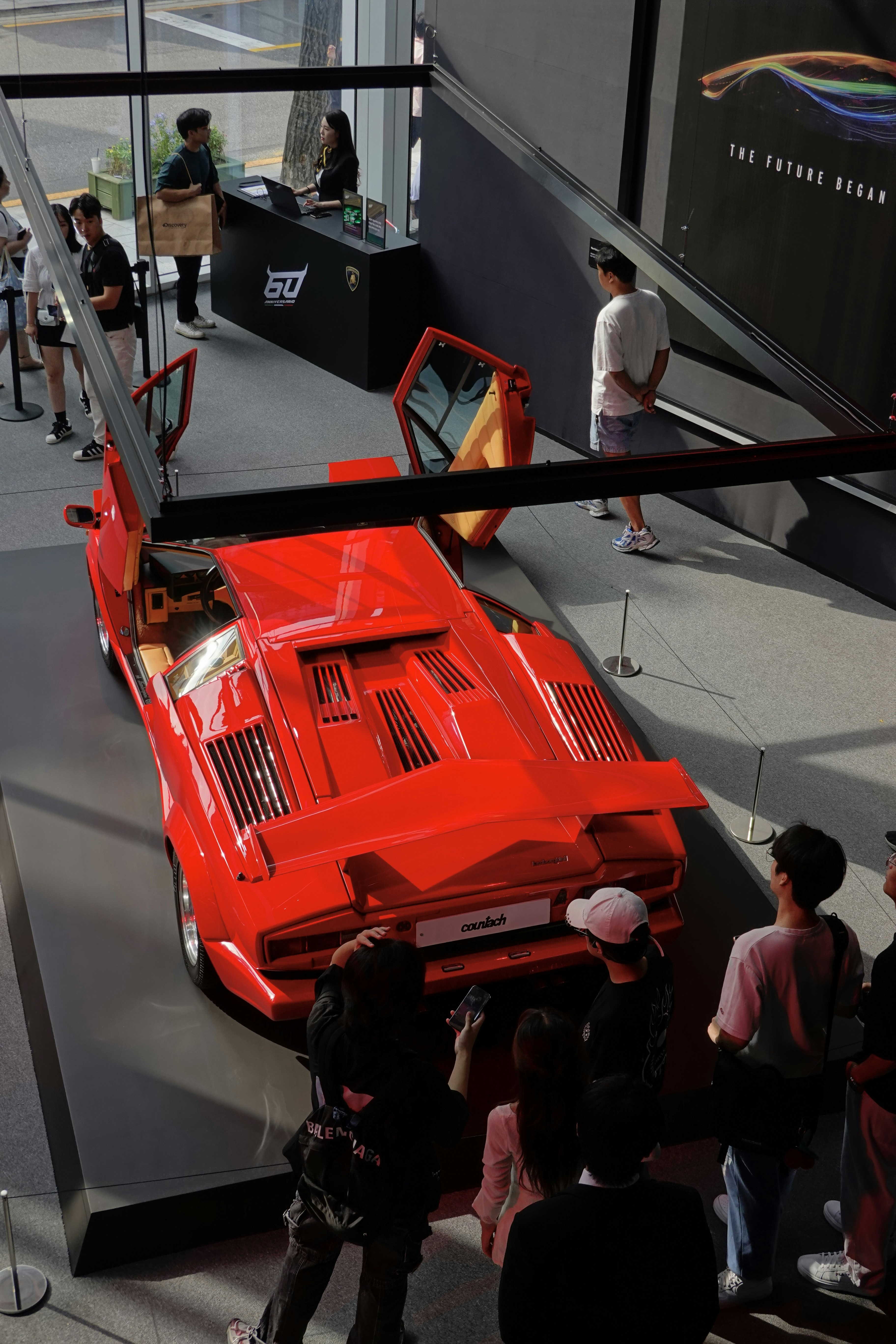 Crimson Feline: Red Supercar on Display Amid Onlookers