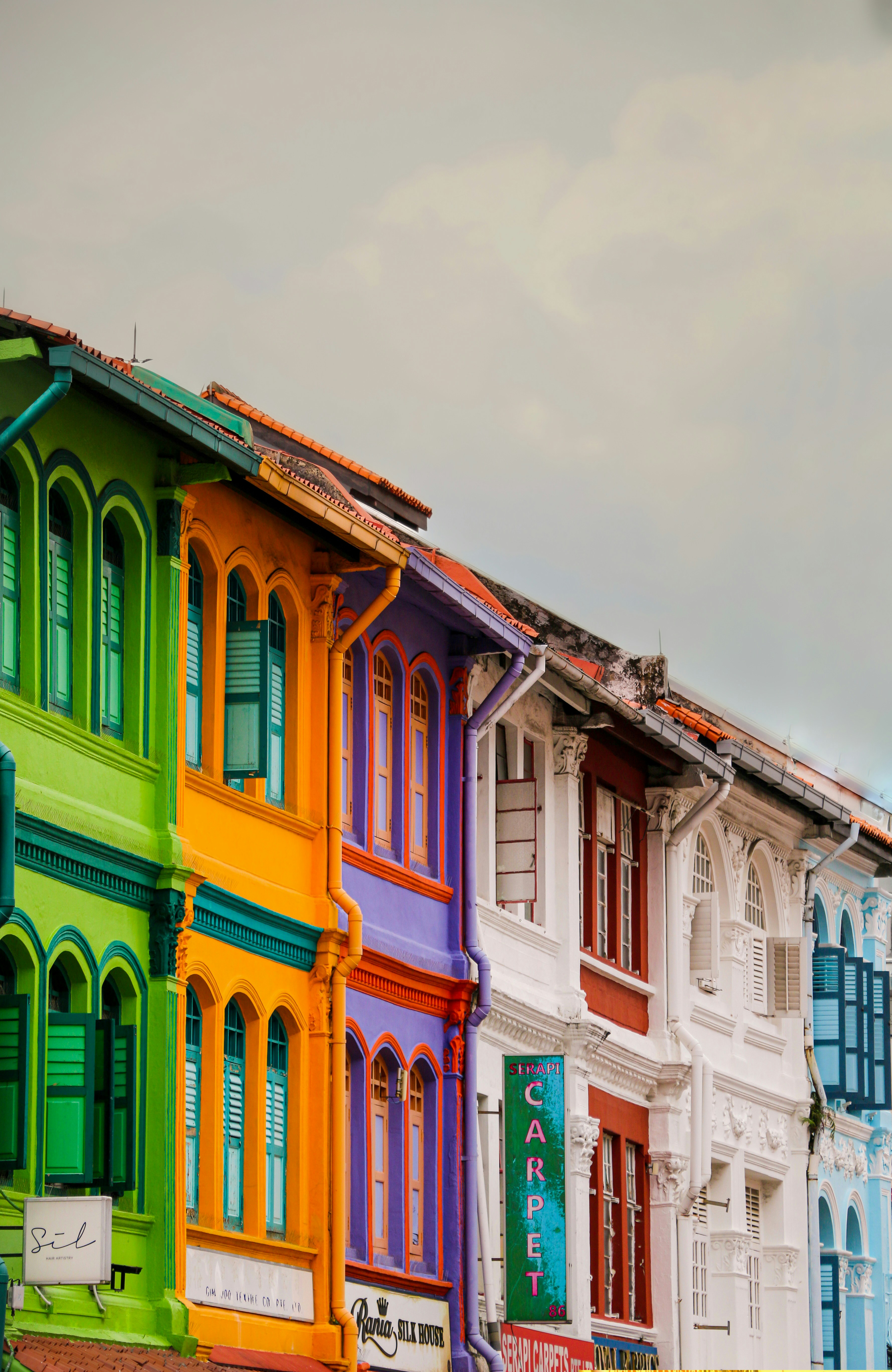 A row of multi - colored houses with a cloudy sky in the background ...