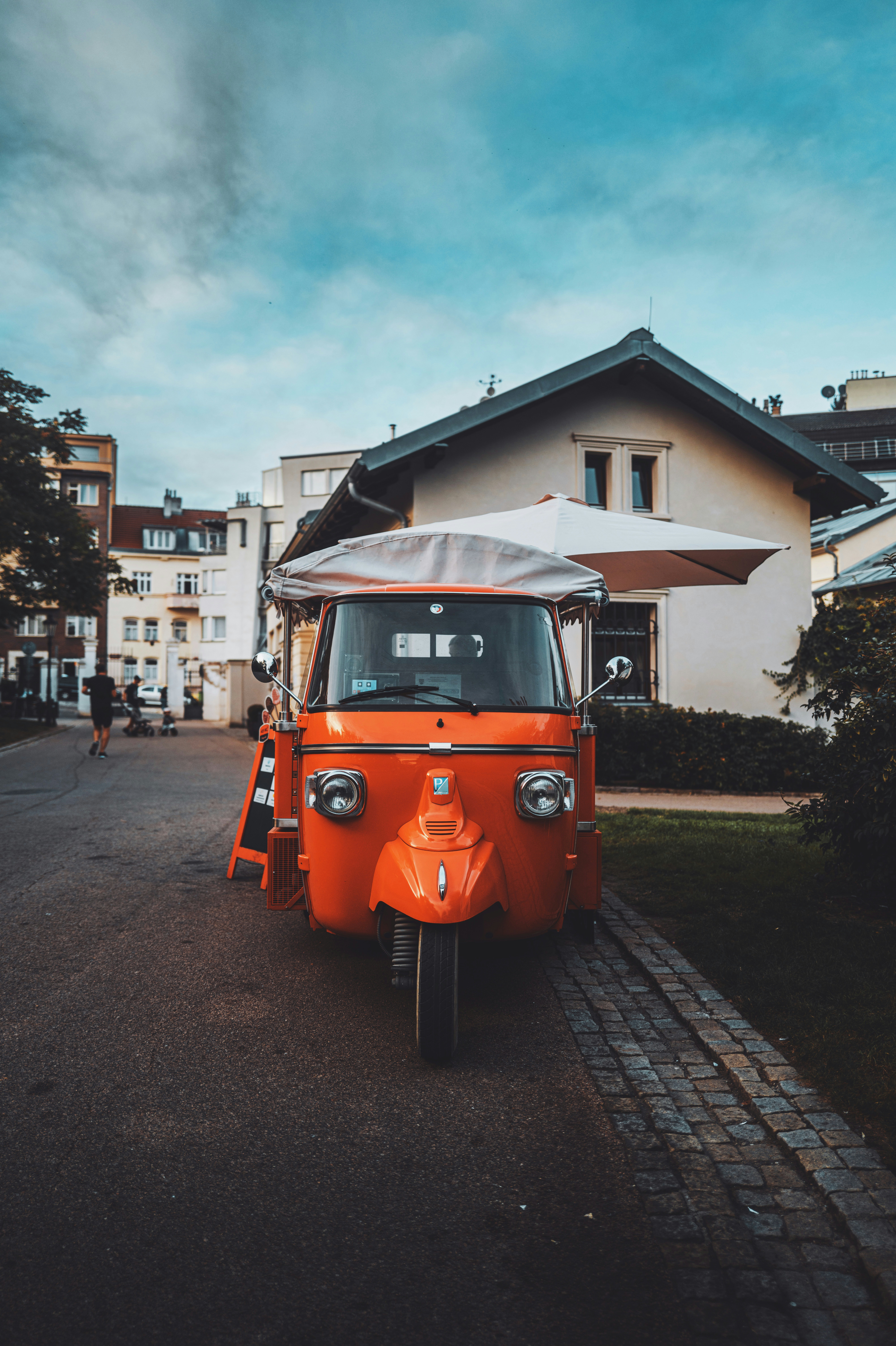Orange Ape on a Cobblestone Street: Retro Three-Wheeler in a Quiet European Neighborhood