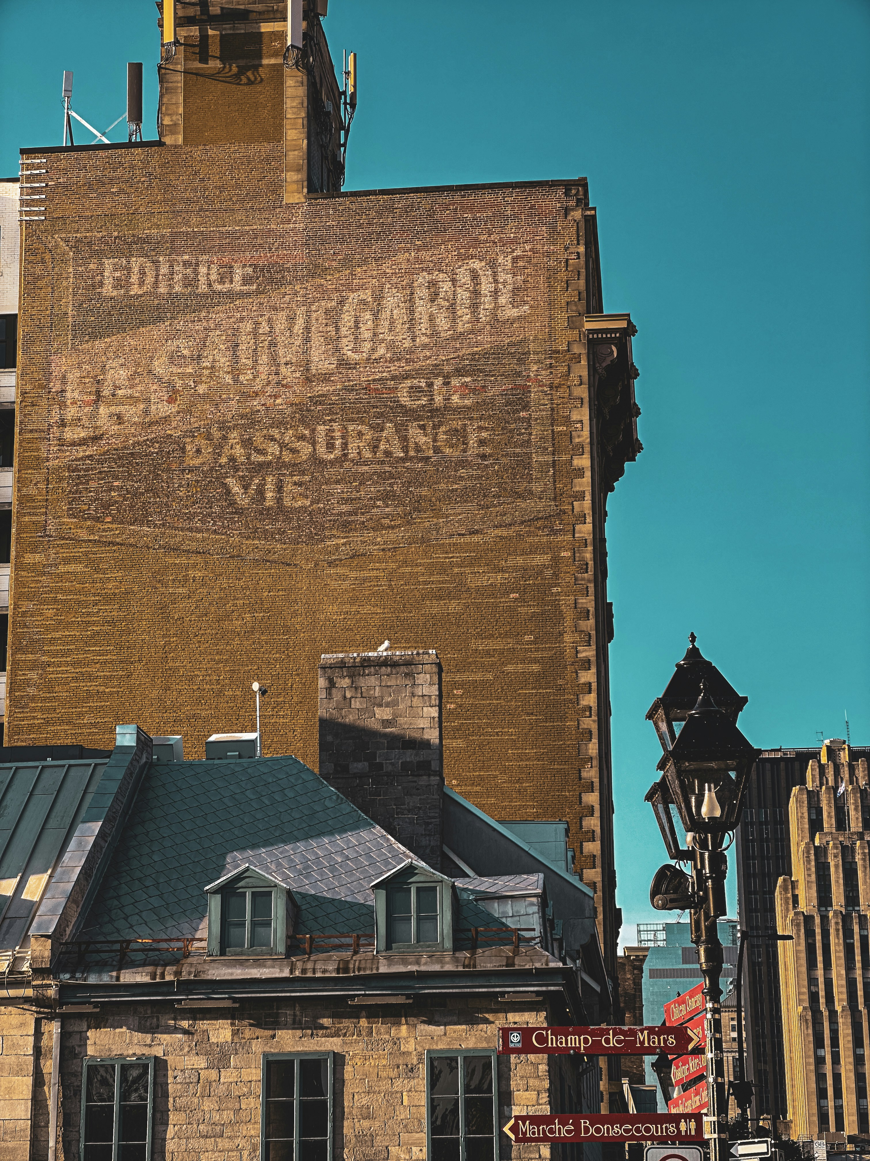 Faded Montreal Ad on a Brick Facade Under a Teal Sky