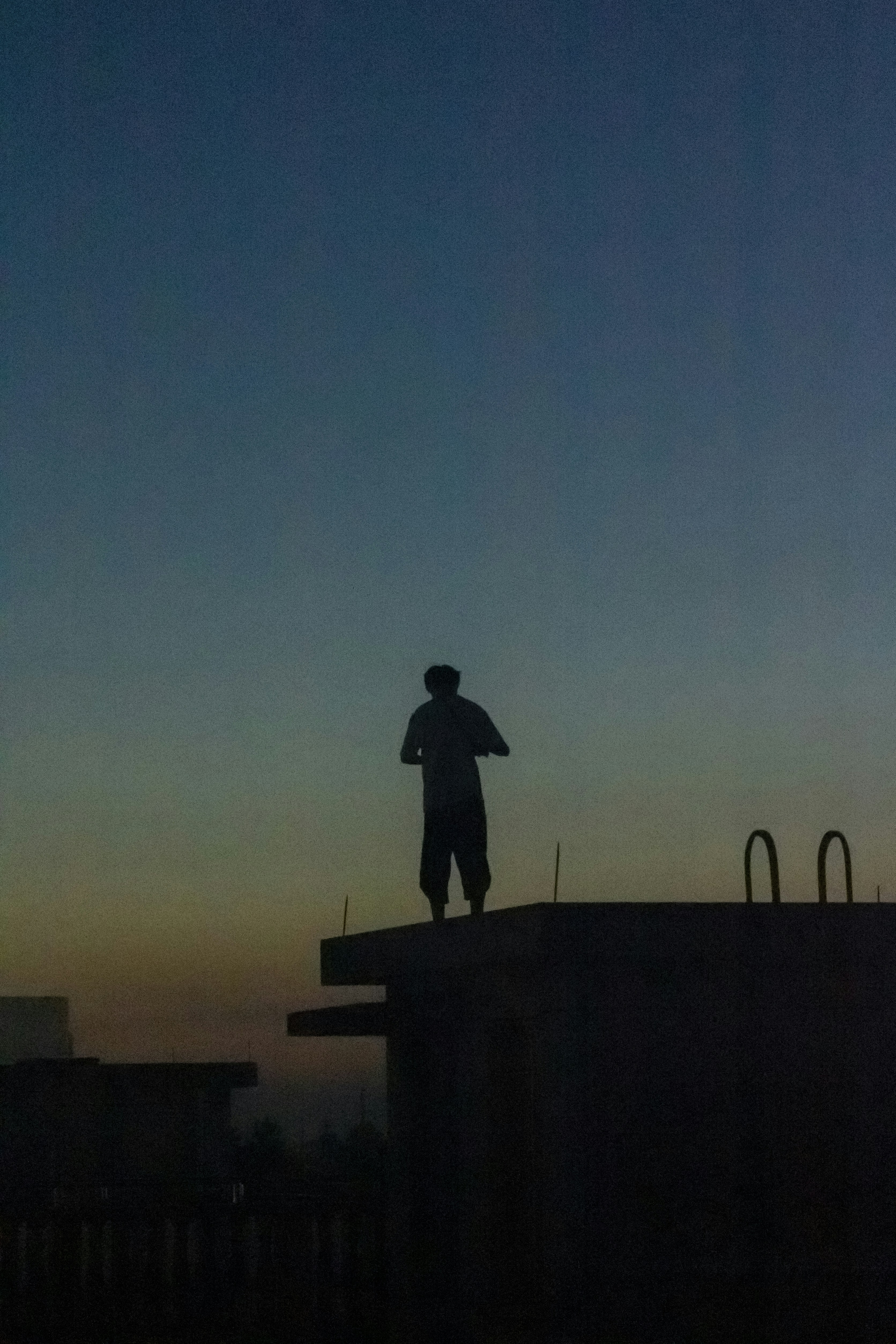 Dusk on the Rooftop: A Lone Silhouette Against the Gradient Sky